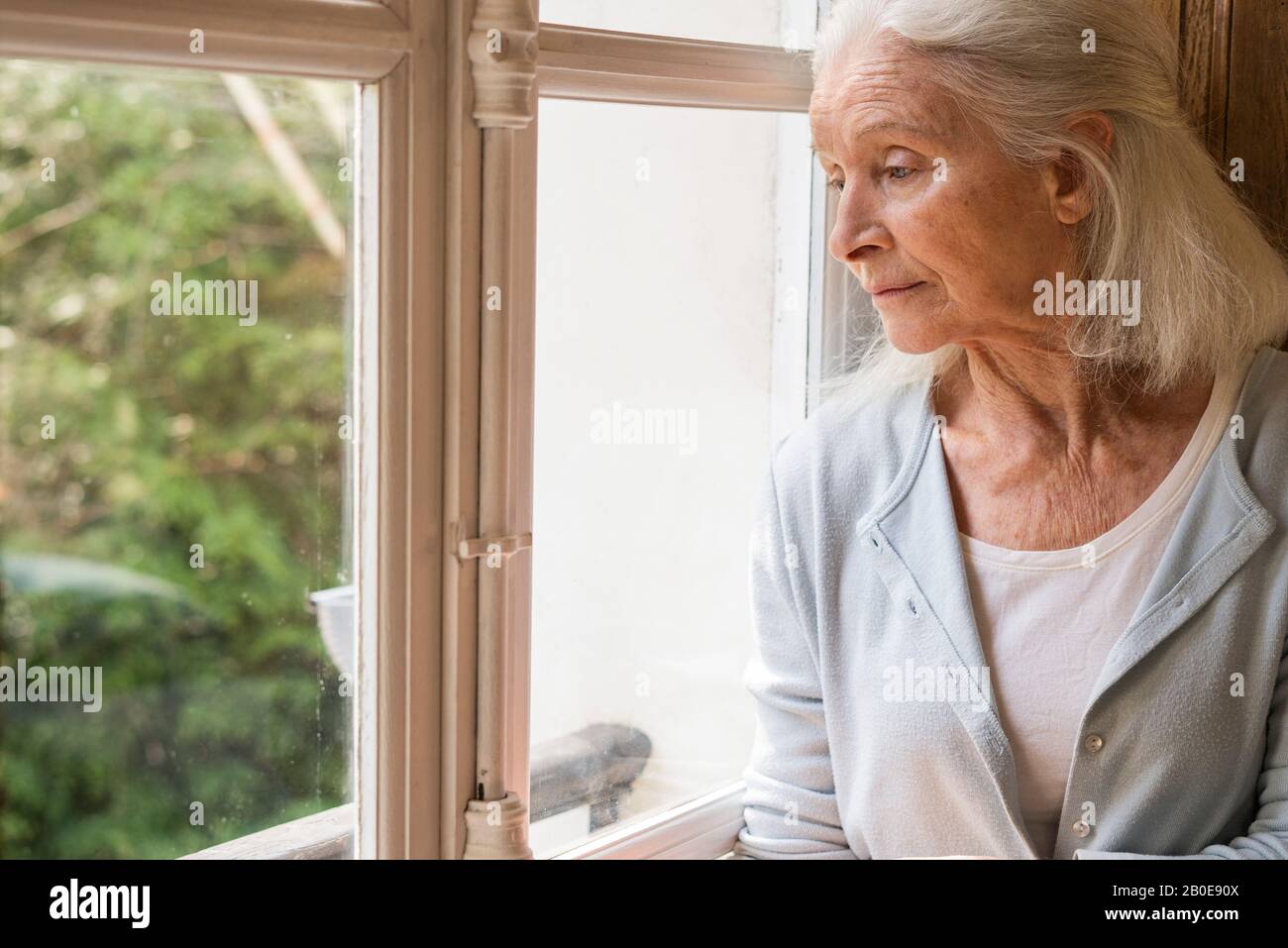 Senior woman standing near window Stock Photo - Alamy
