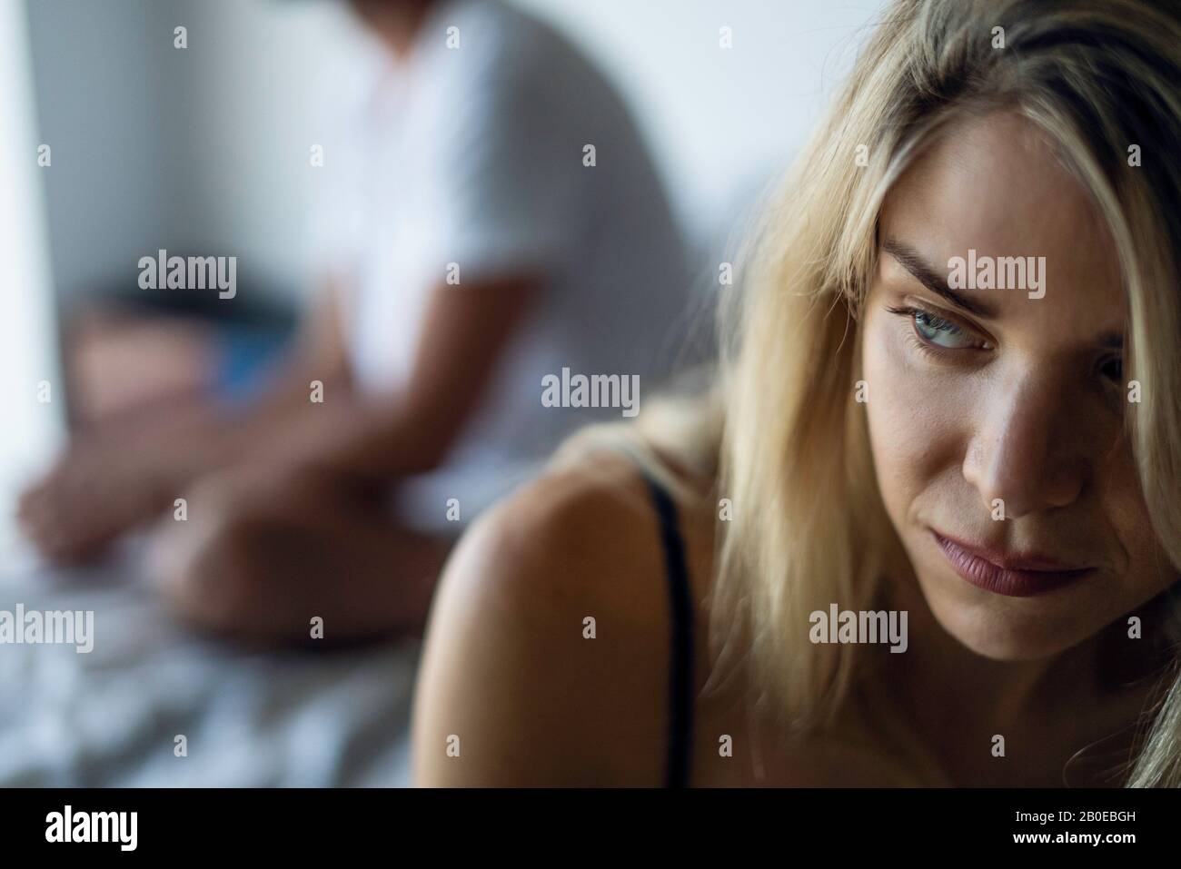 Sad woman sitting on bed Stock Photo - Alamy