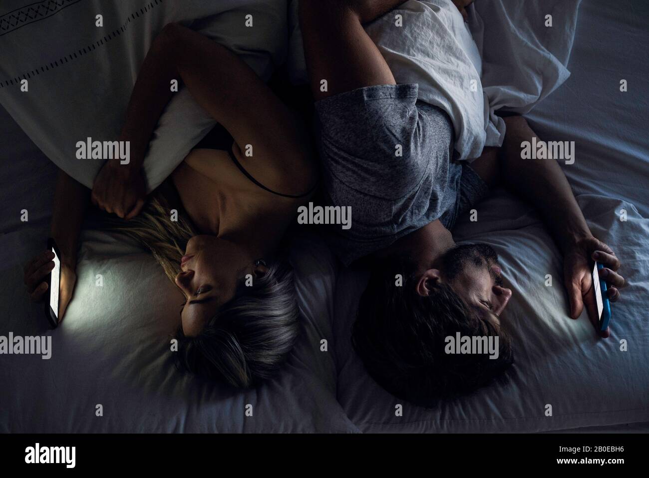 Young couple using smartphones on bed Stock Photo - Alamy