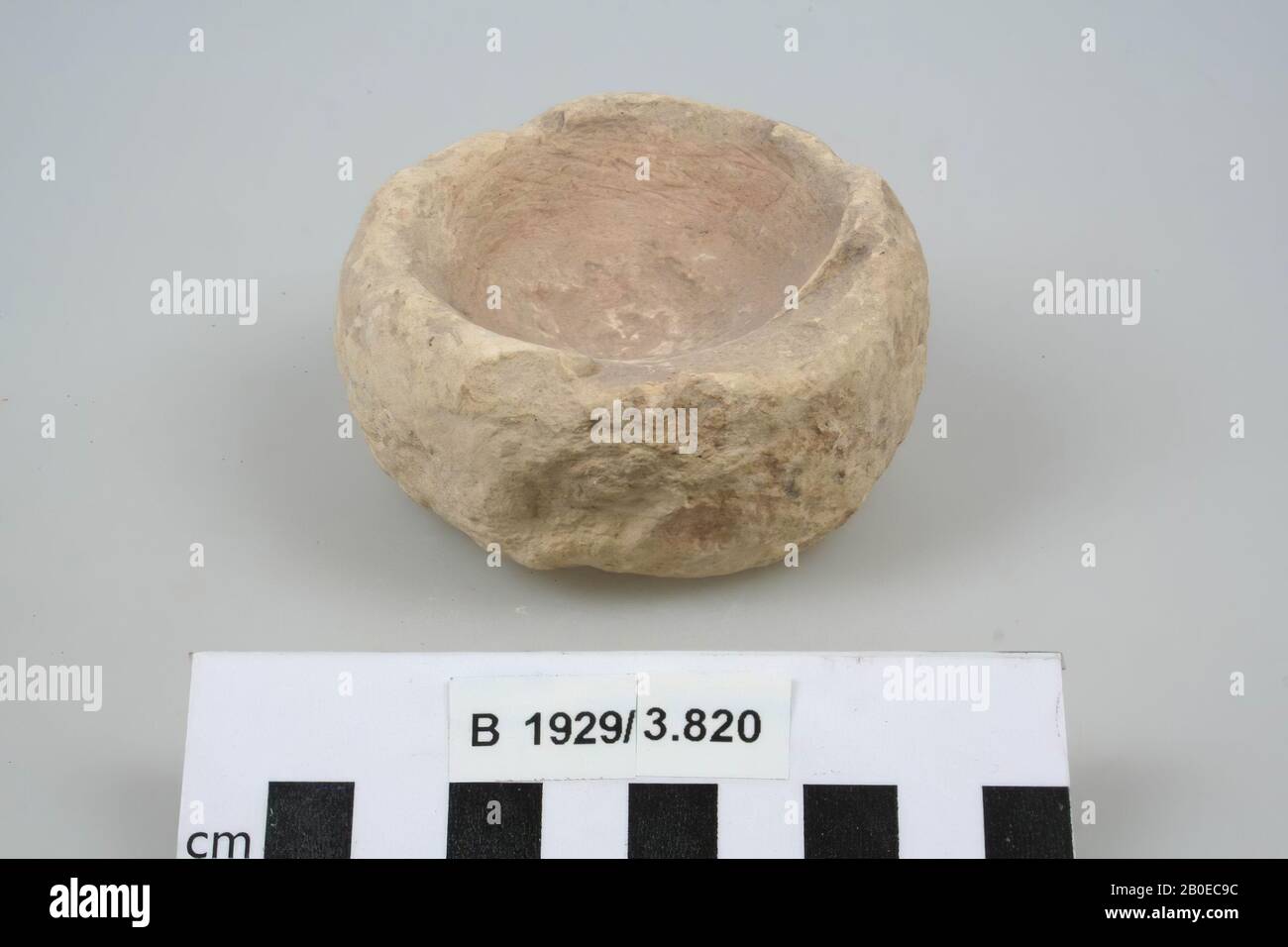 A hollowed stone used as a mortar. The outer edges are roughly worked ...