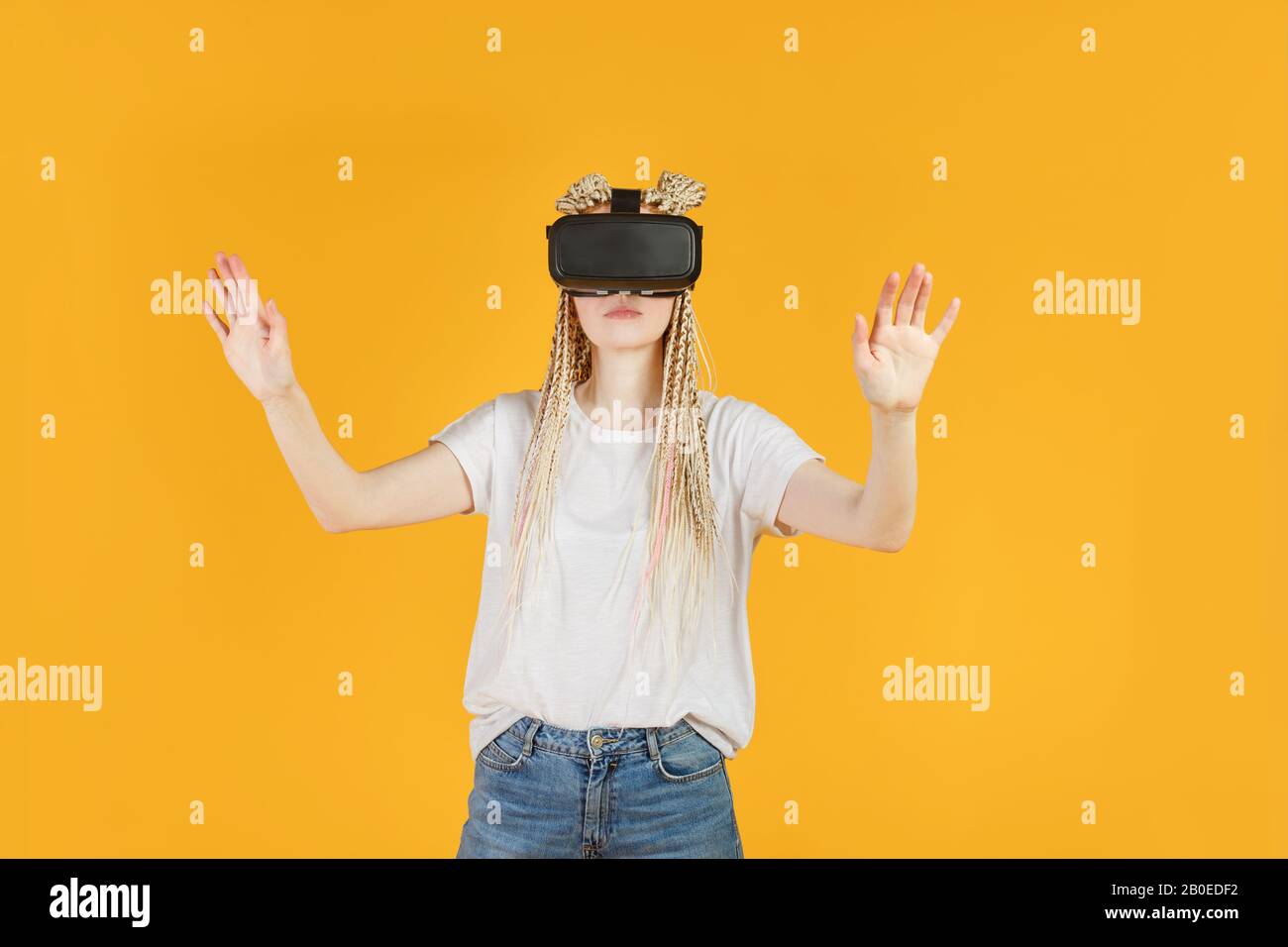 Young woman experience with virtual reality. Woman on yellow background ...