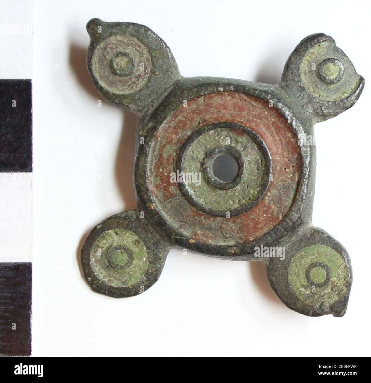 Fibula of bronze. Round disc filled with red enamel and surrounded by 4 ...