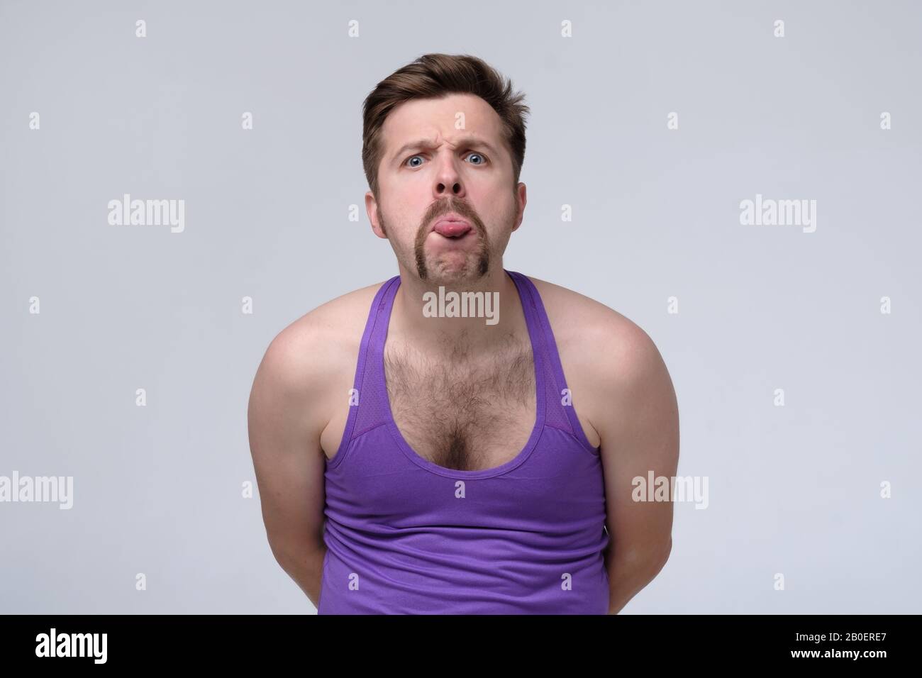 Sportive man with funny mustache sticking out his tongue, teasing ...