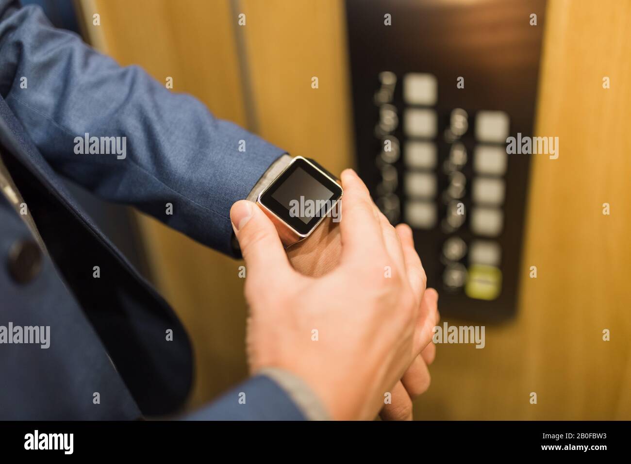 Close up of businessman looking at blank screen smart watch in elevator ...