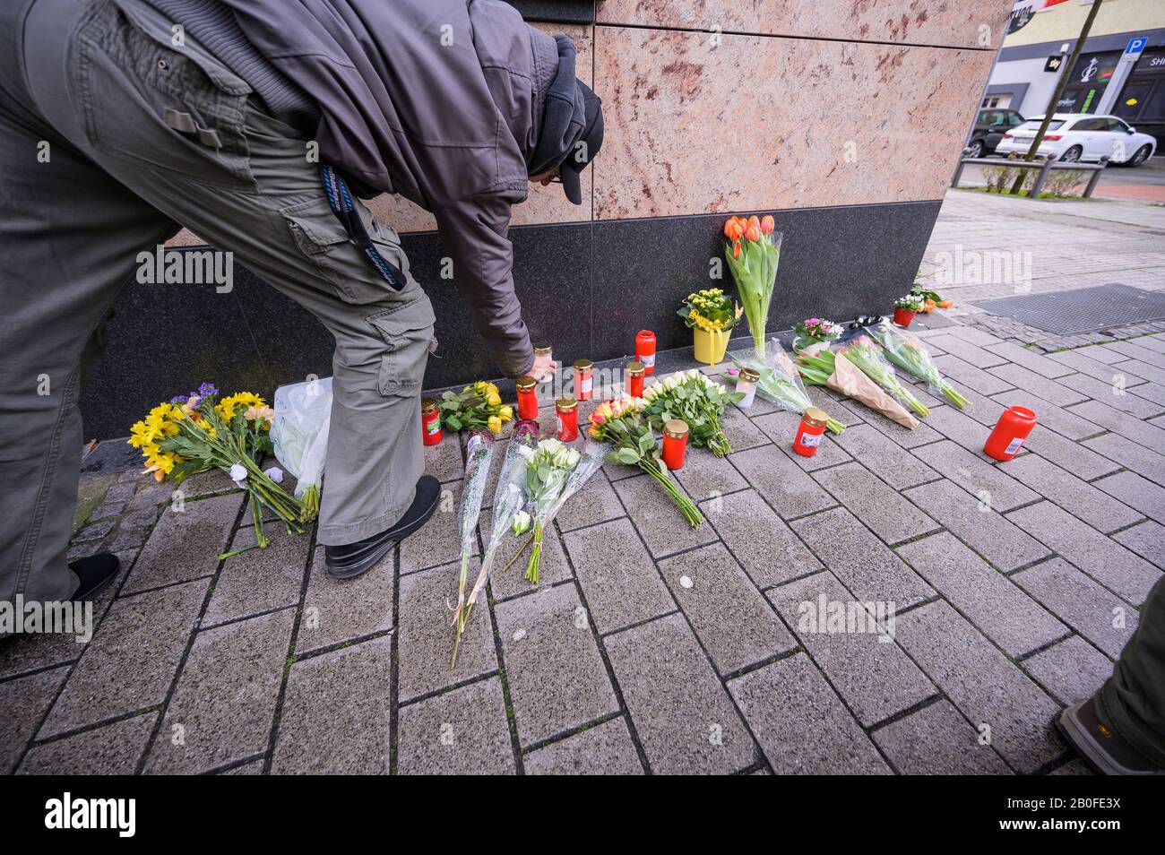 Hanau, Germany. 20th Feb, 2020. A man lays flowers in the hay market ...
