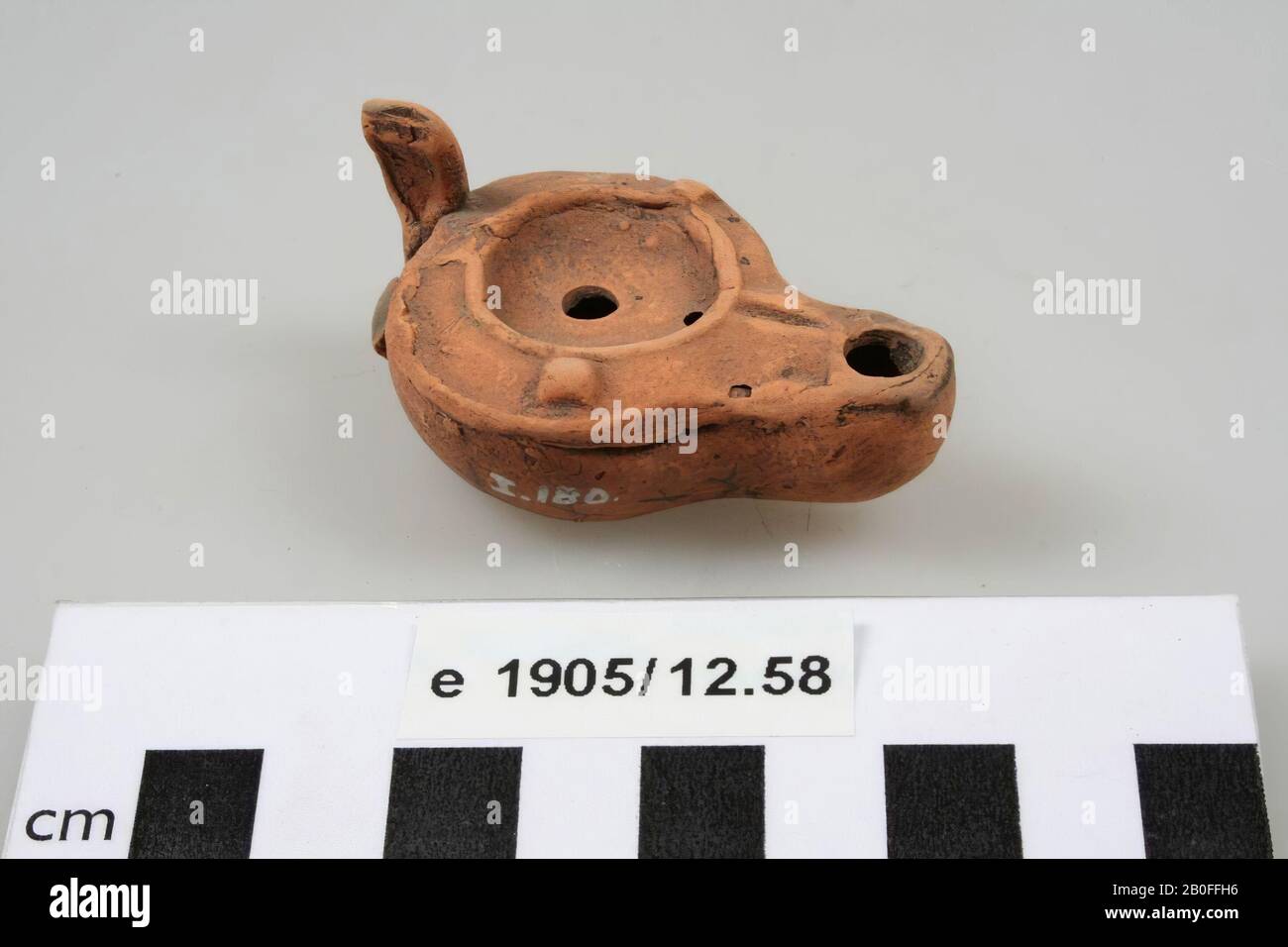 Terracotta oil lamp, with (partly broken) ear, spout, filler hole, fire ...