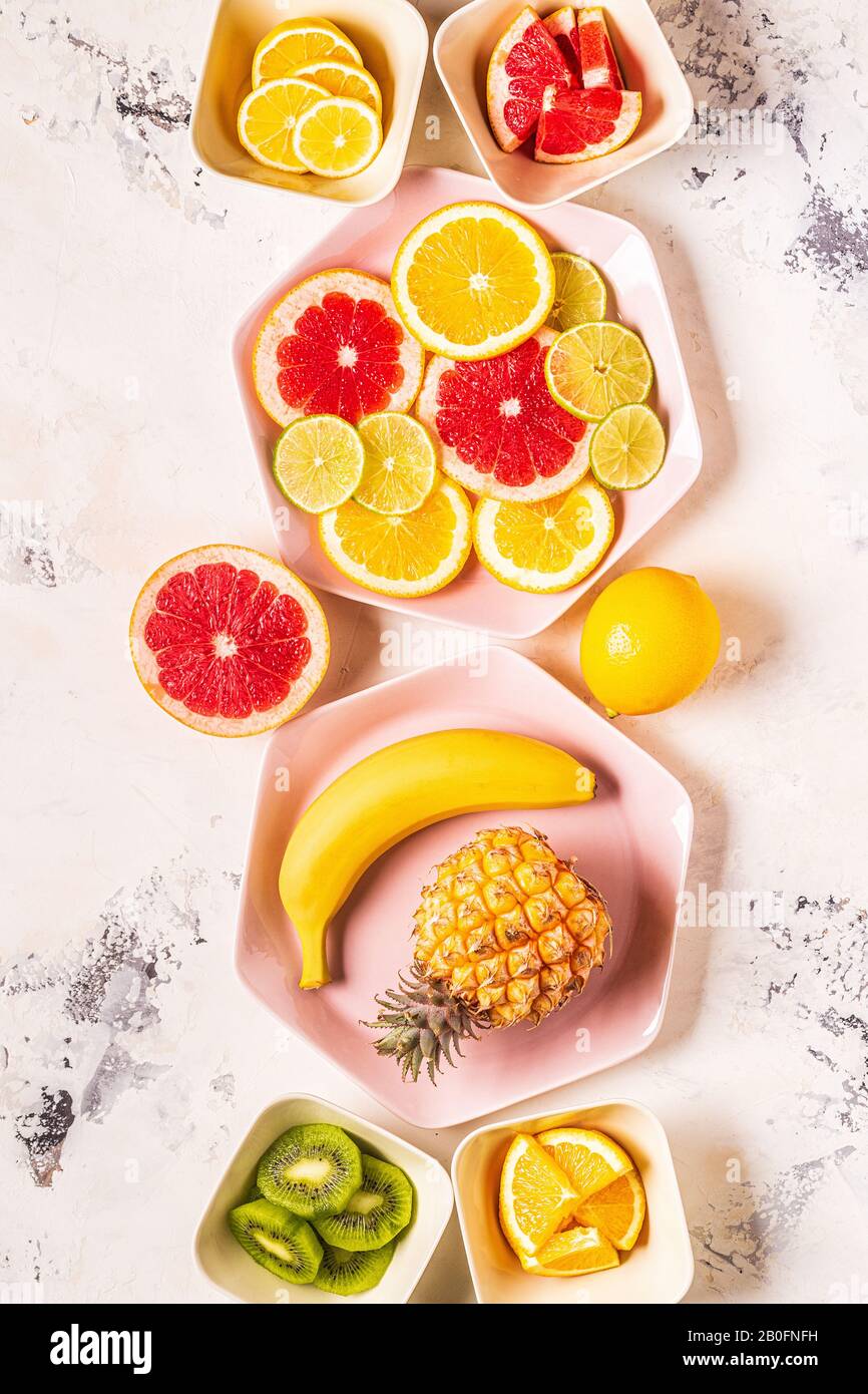 Tropical fruits whole and slices on plates, top view Stock Photo - Alamy
