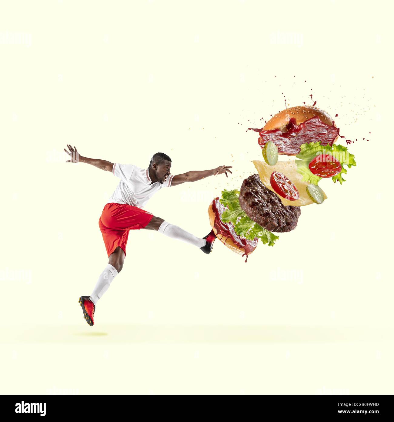 Soccer player kicking burger like ball in jump on yellow background ...
