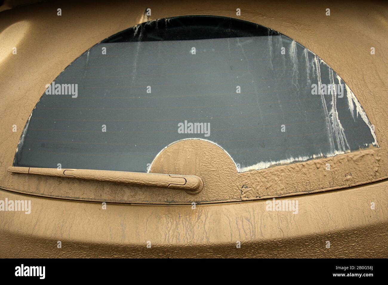 The detail of the rear window of a car, completely covered by mud. The ...