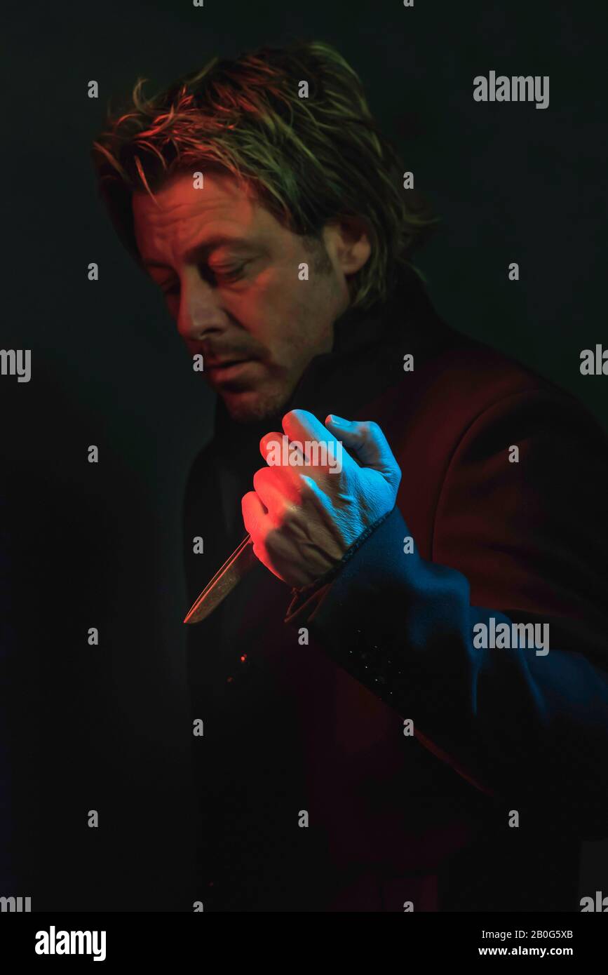 Scary man with scissors in hand illuminated by red and blue light Stock ...