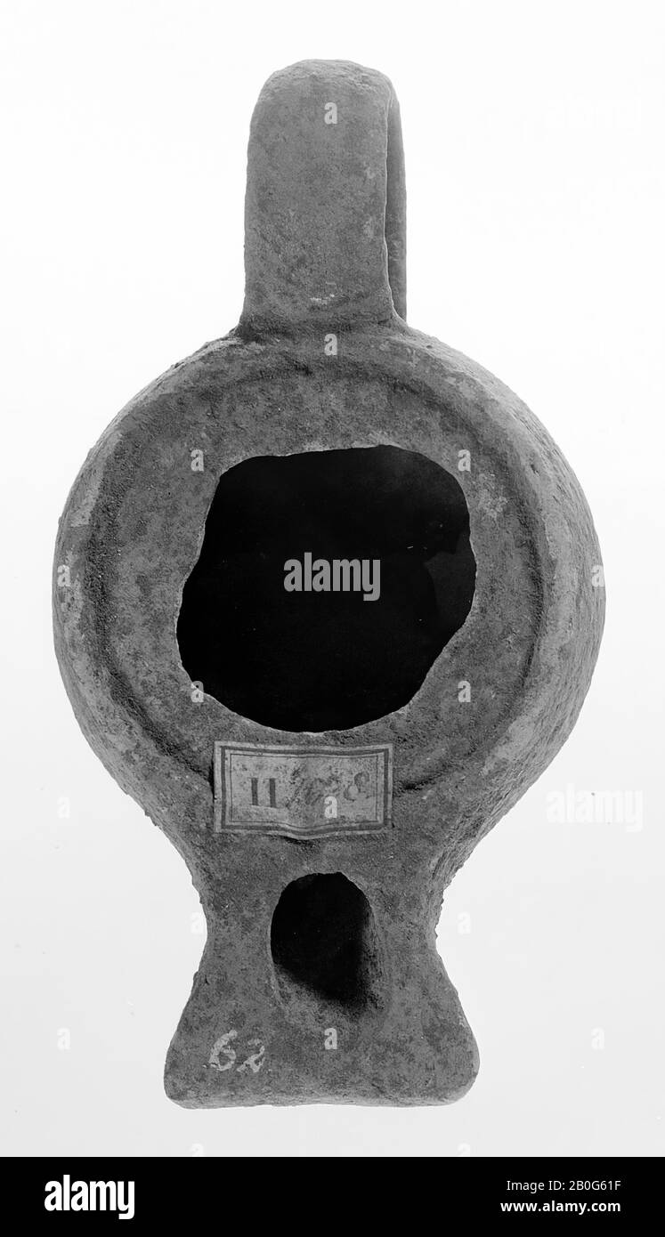 A crude oil lamp of gray earthenware with a rounded body and wide ...