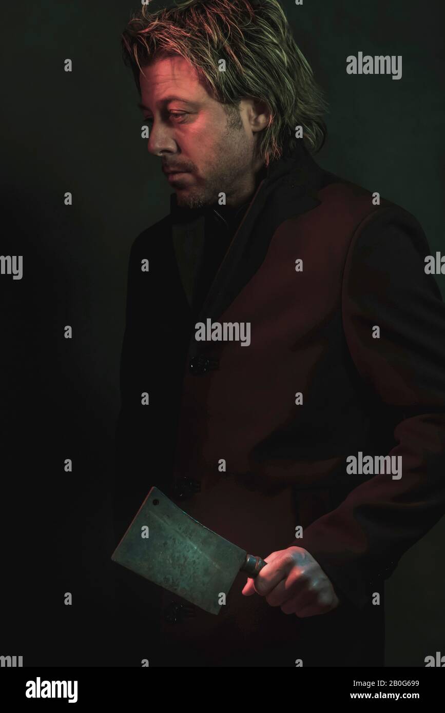 Threatening man with cleaver in hand illuminated by red and blue light ...