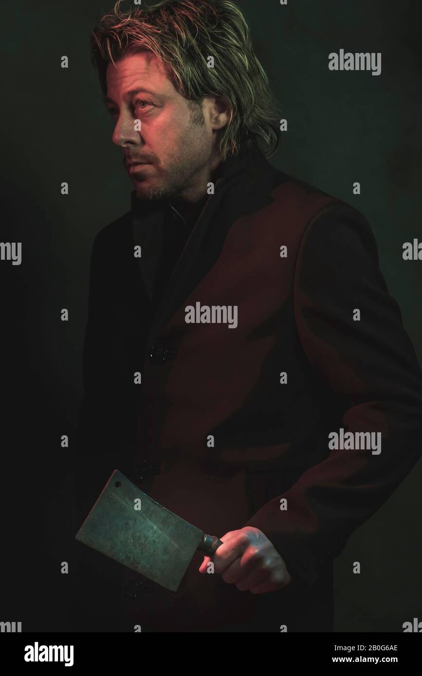 Threatening man with cleaver in hand illuminated by red and blue light ...