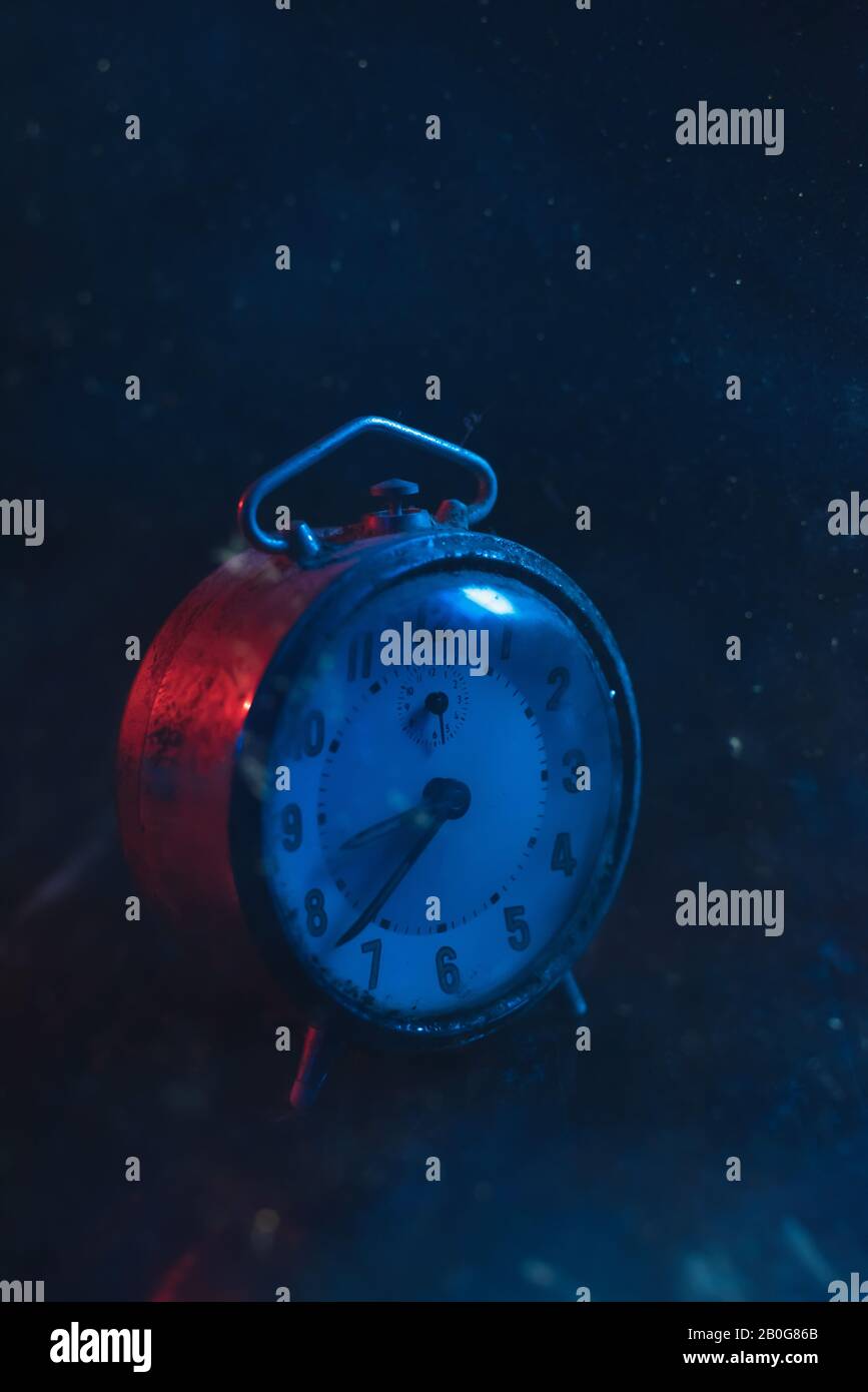 Dusty old alarm clock on worn wooden table at night Stock Photo - Alamy