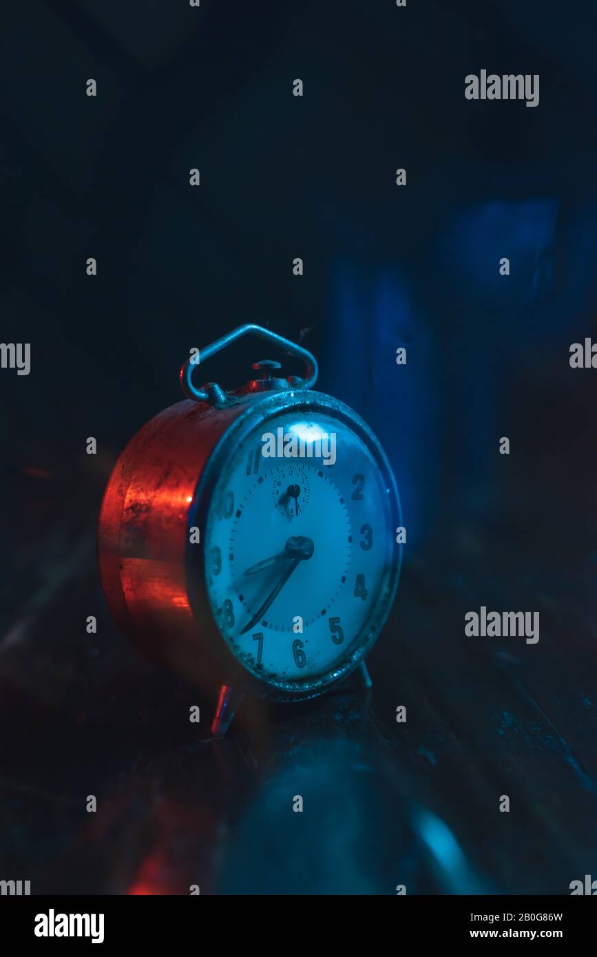 Dusty old alarm clock on worn wooden table at night Stock Photo - Alamy