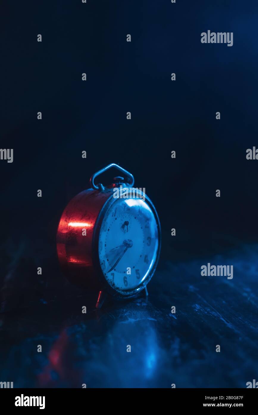 Dusty old alarm clock on worn wooden table at night Stock Photo - Alamy