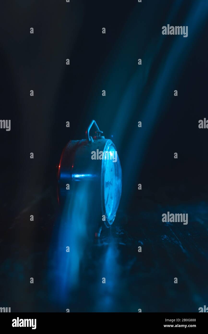 Dusty old alarm clock on worn wooden table at night. Side view Stock ...