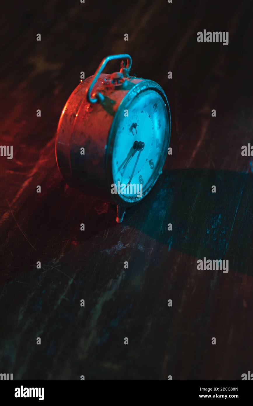 Dusty old alarm clock on worn wooden table at night Stock Photo - Alamy