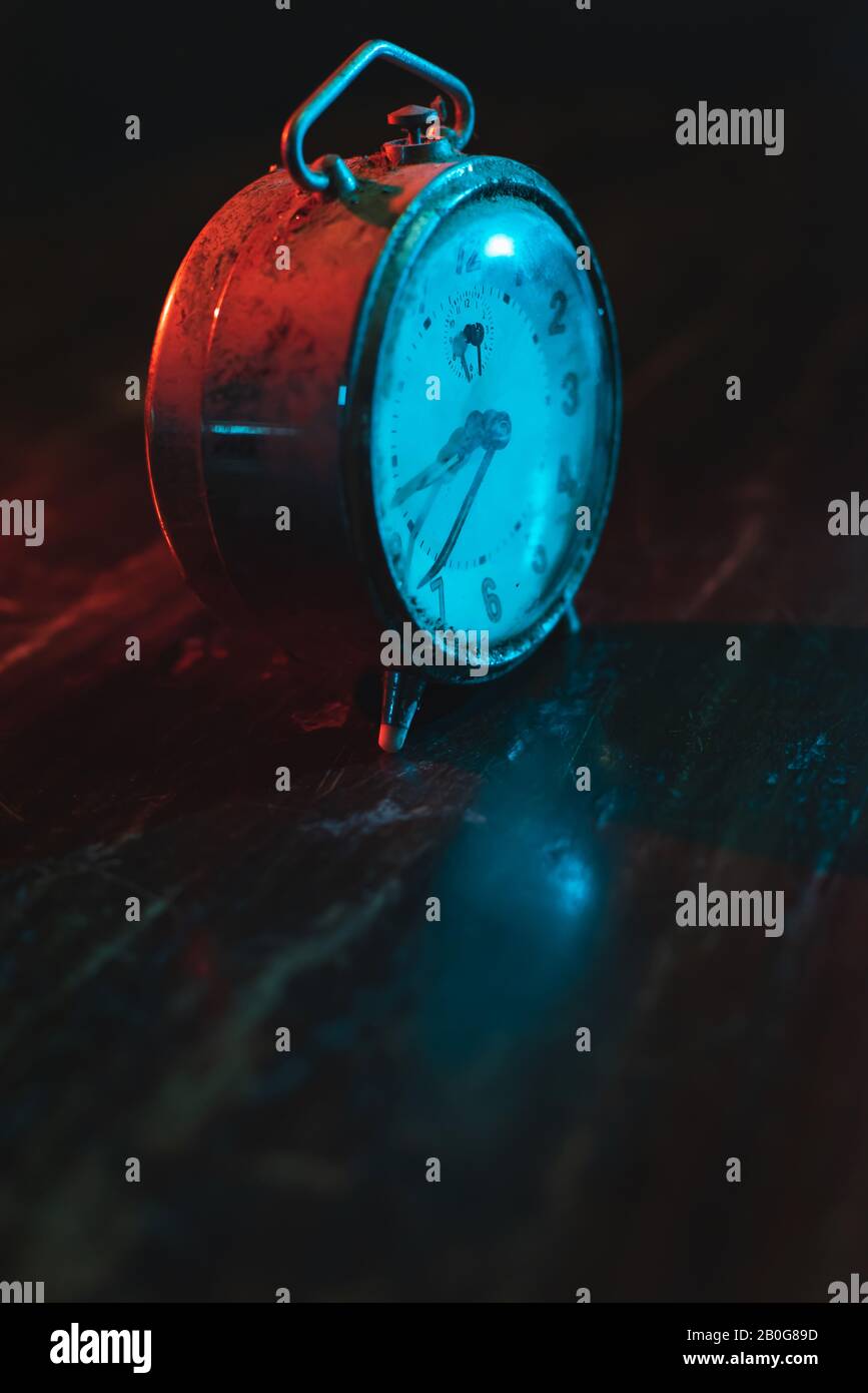 Dusty old alarm clock on worn wooden table at night Stock Photo - Alamy