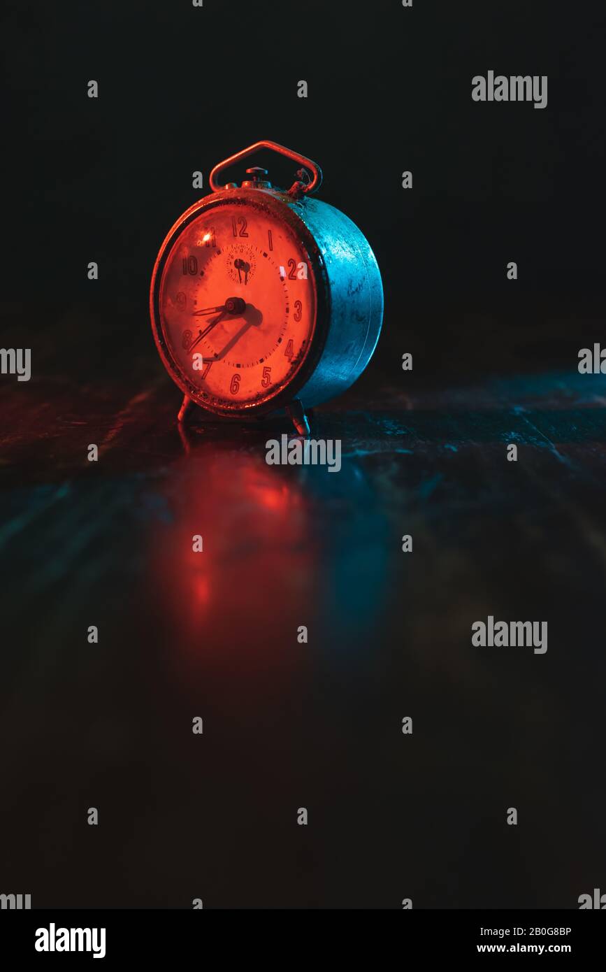 Dusty old alarm clock on worn wooden table at night Stock Photo - Alamy