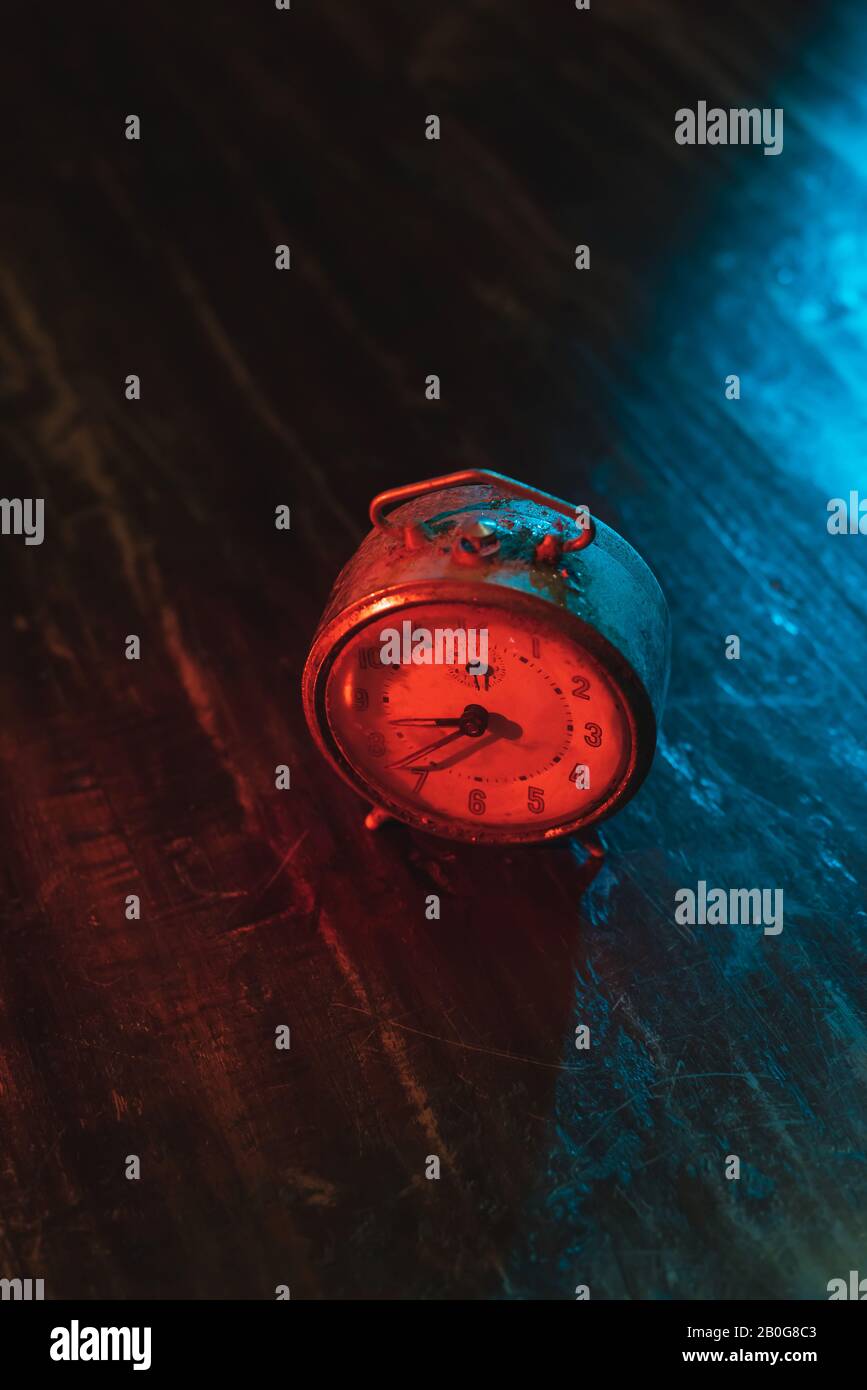 Dusty old alarm clock on worn wooden table at night Stock Photo - Alamy
