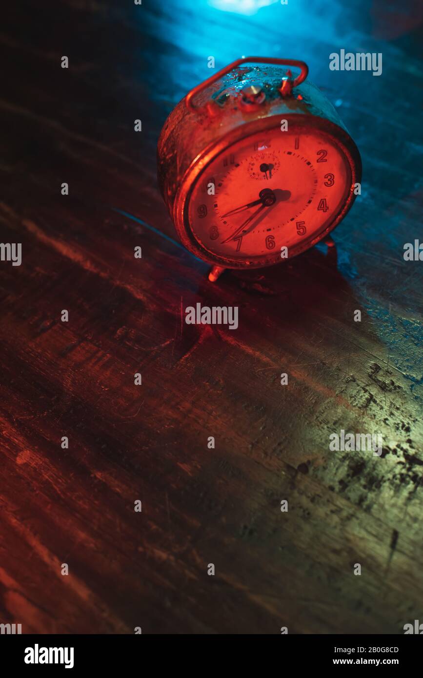 Dusty old alarm clock on worn wooden table at night Stock Photo - Alamy
