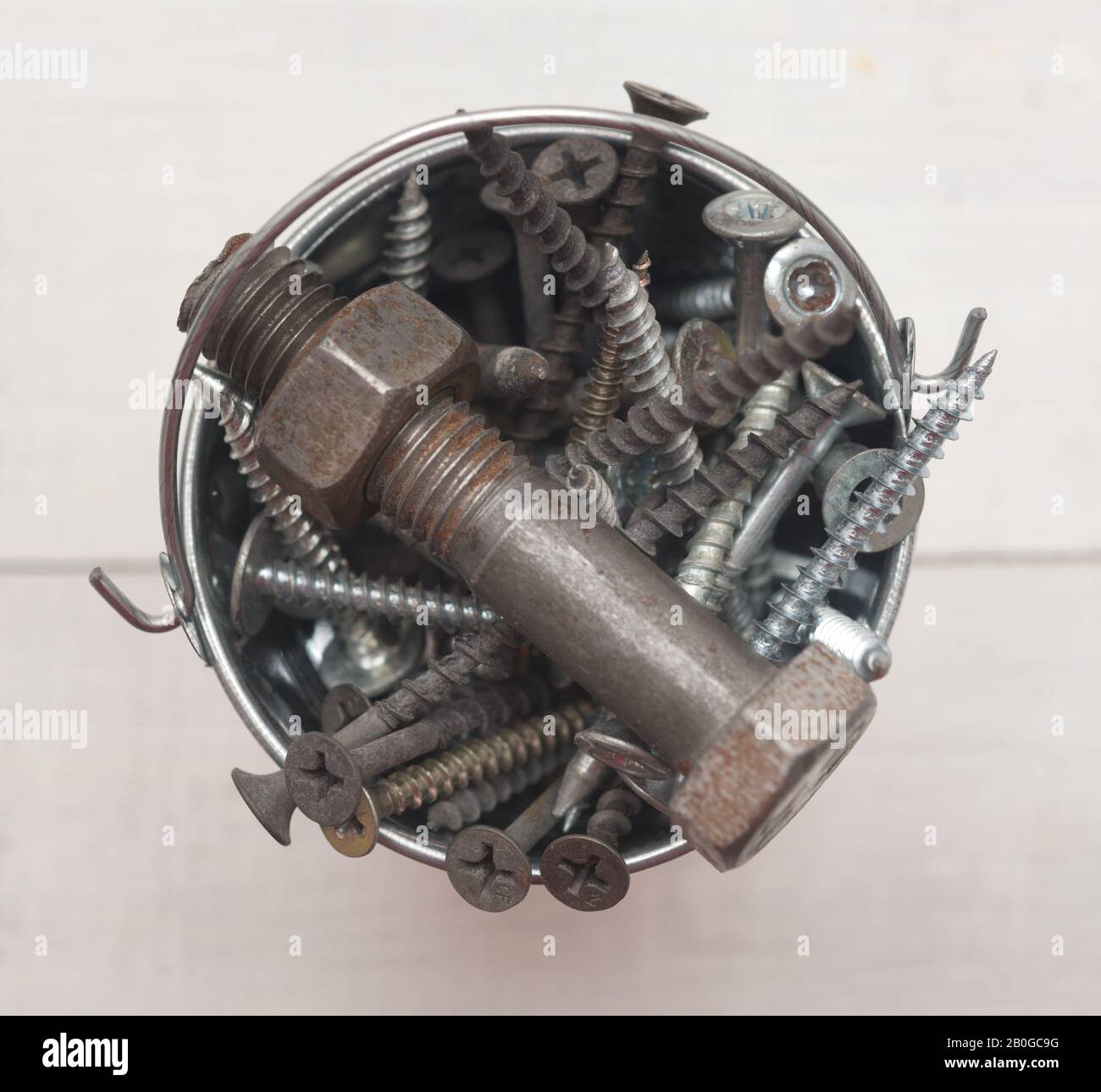 Screws and bolts in a bucket on a wooden background Stock Photo - Alamy