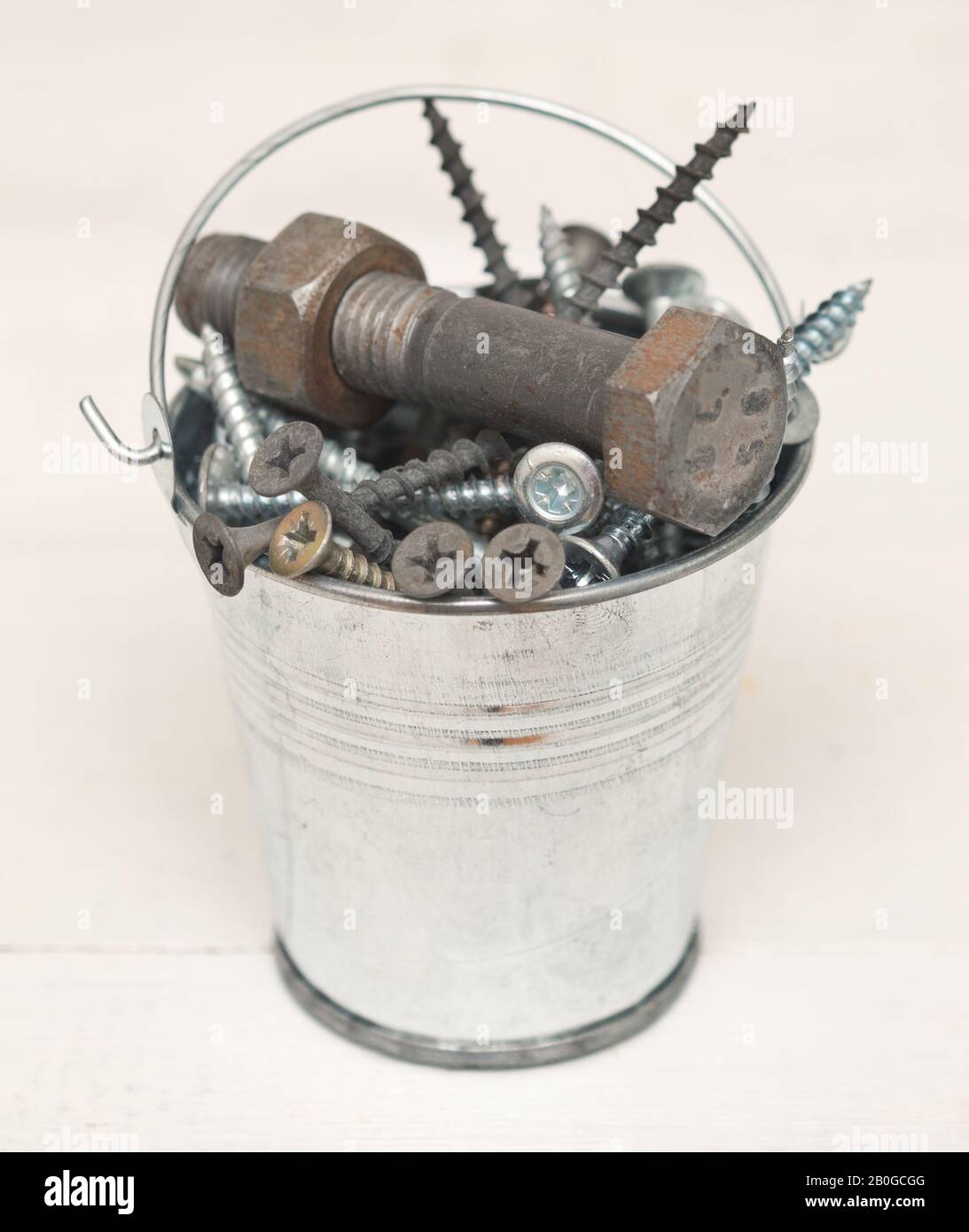 Screws and bolts in a bucket on a wooden background Stock Photo - Alamy