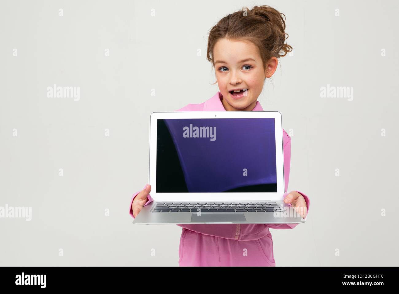 attractive charming young girl in a pink suit shows a laptop screen ...