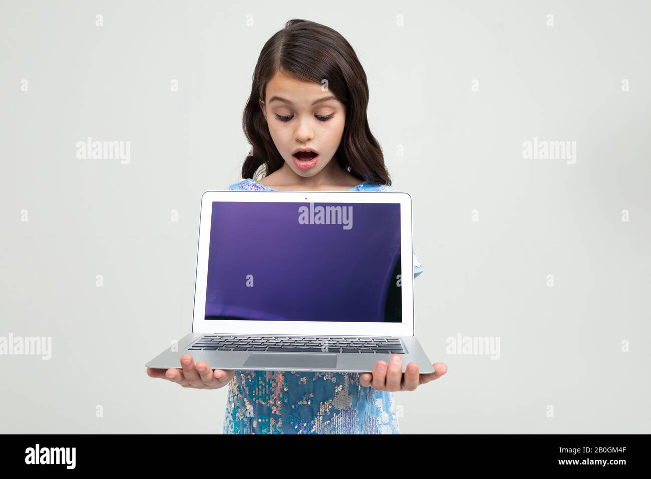 surprised teenager girl holding a laptop with a mockup for inserting a ...