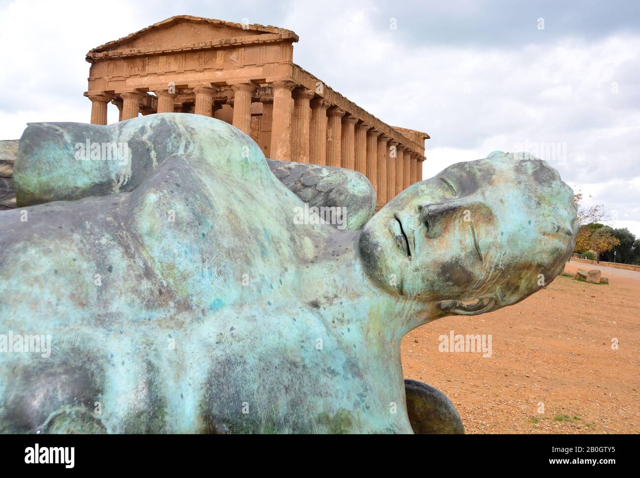 Statue of fallen Icarus in bronze in front of the 2,400 year old Temple ...