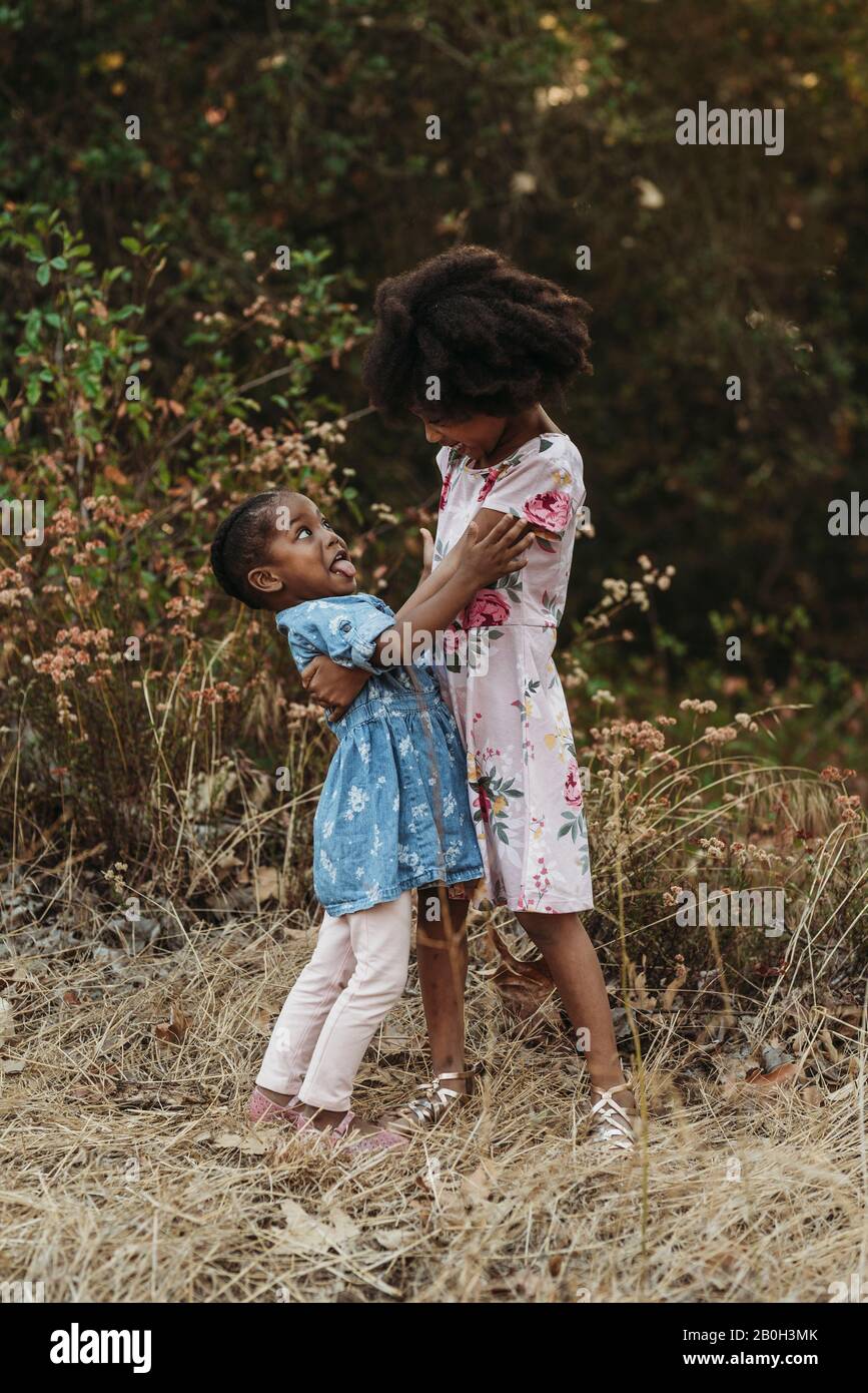 Two sisters laughing and smiling at each other in field Stock Photo - Alamy