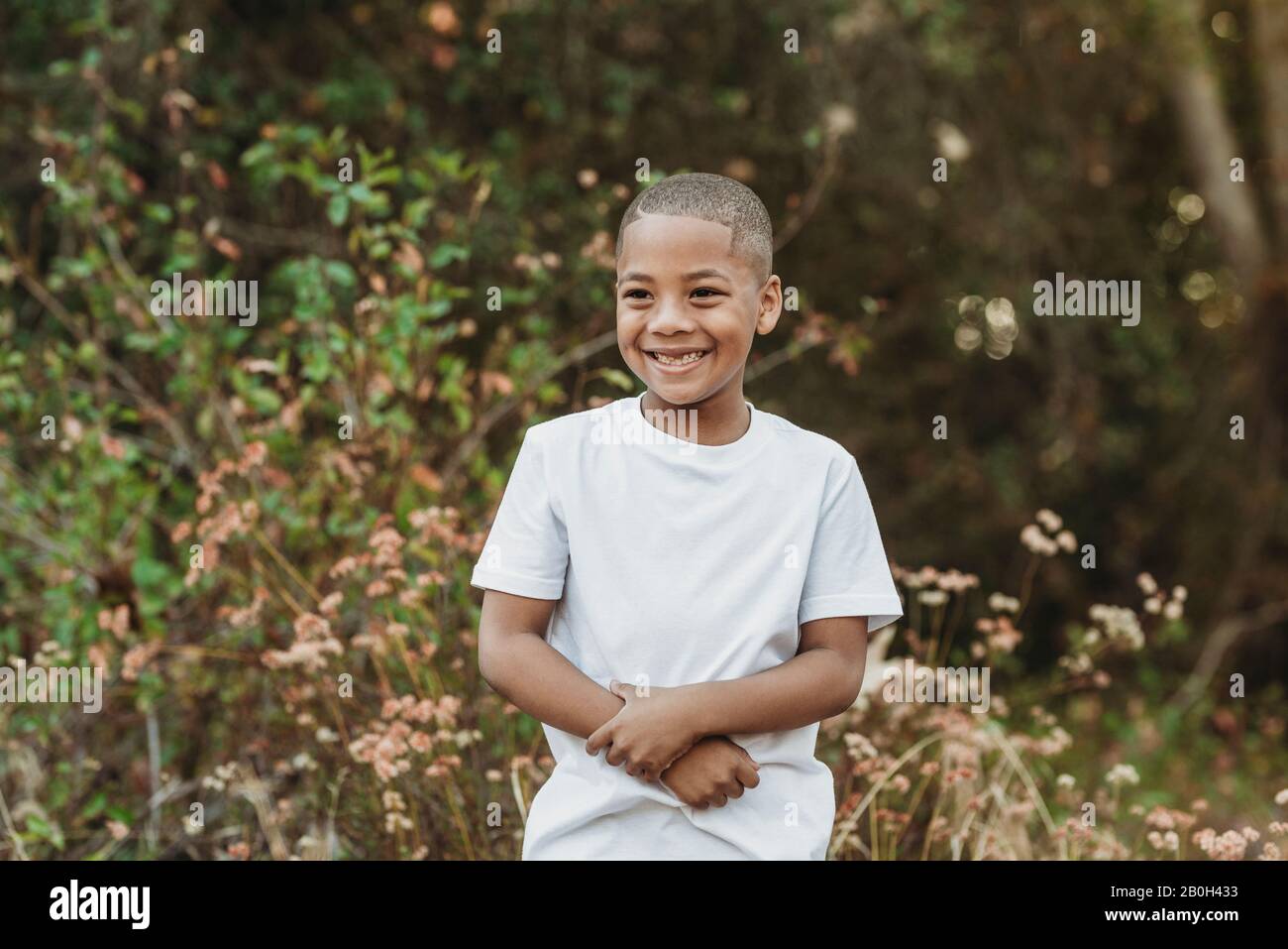 Close up portrait of young school-aged confident boy smiling outside ...