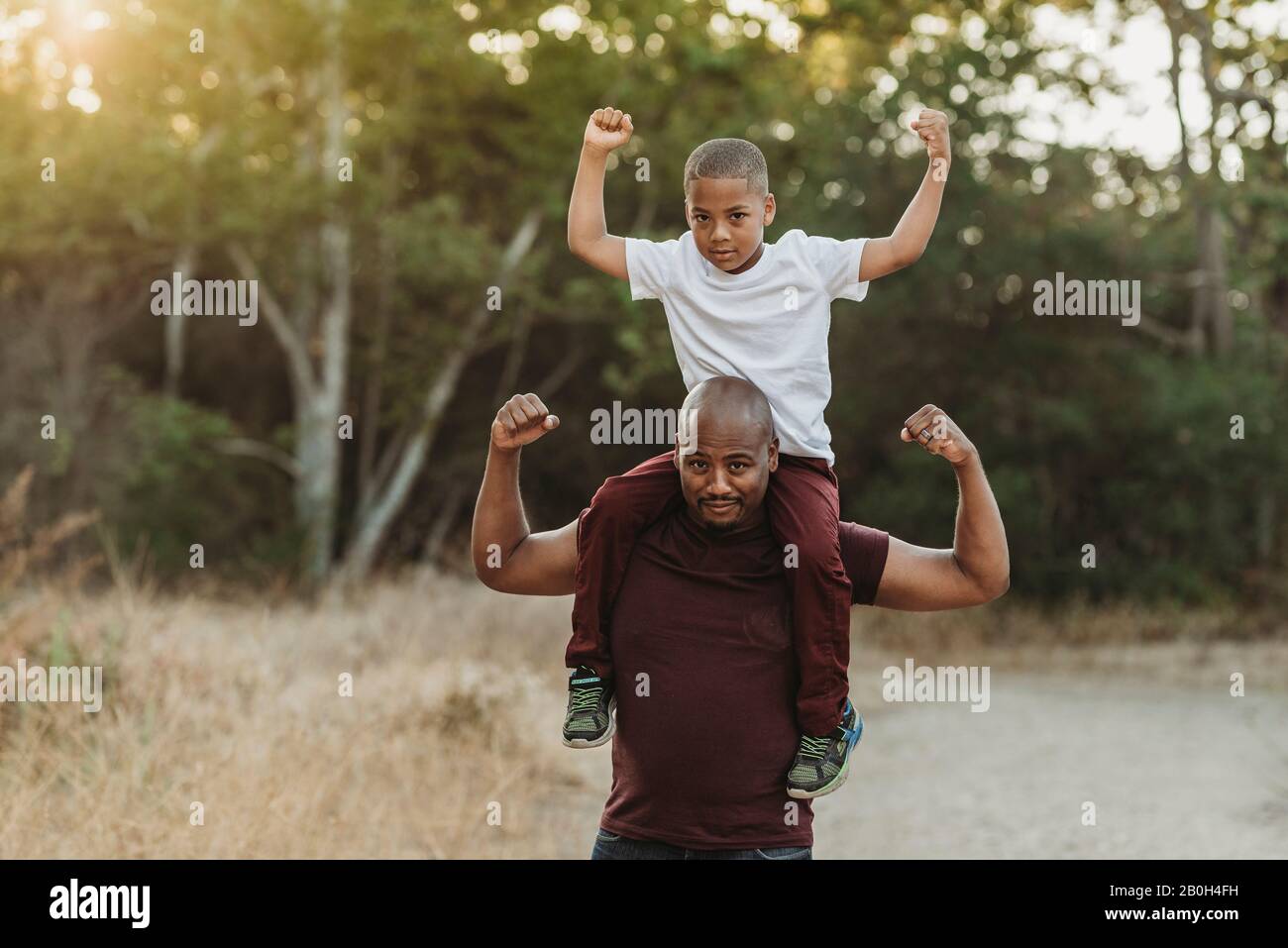 Close up portrait of school-aged son sitting on father's shoulders ...