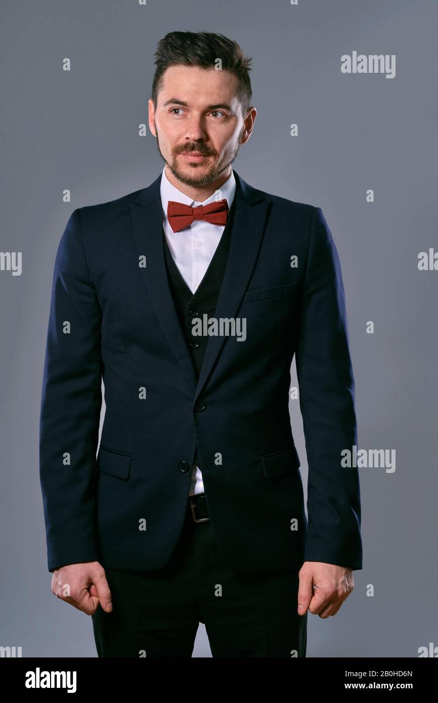 Young business man in classic black suit, white shirt and red bow-tie ...