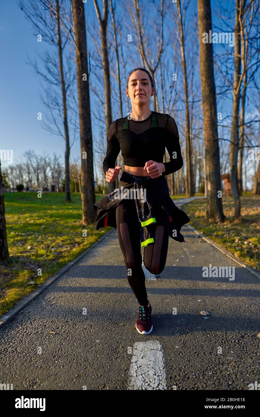 Athletic woman in track suit running in the park Stock Photo - Alamy