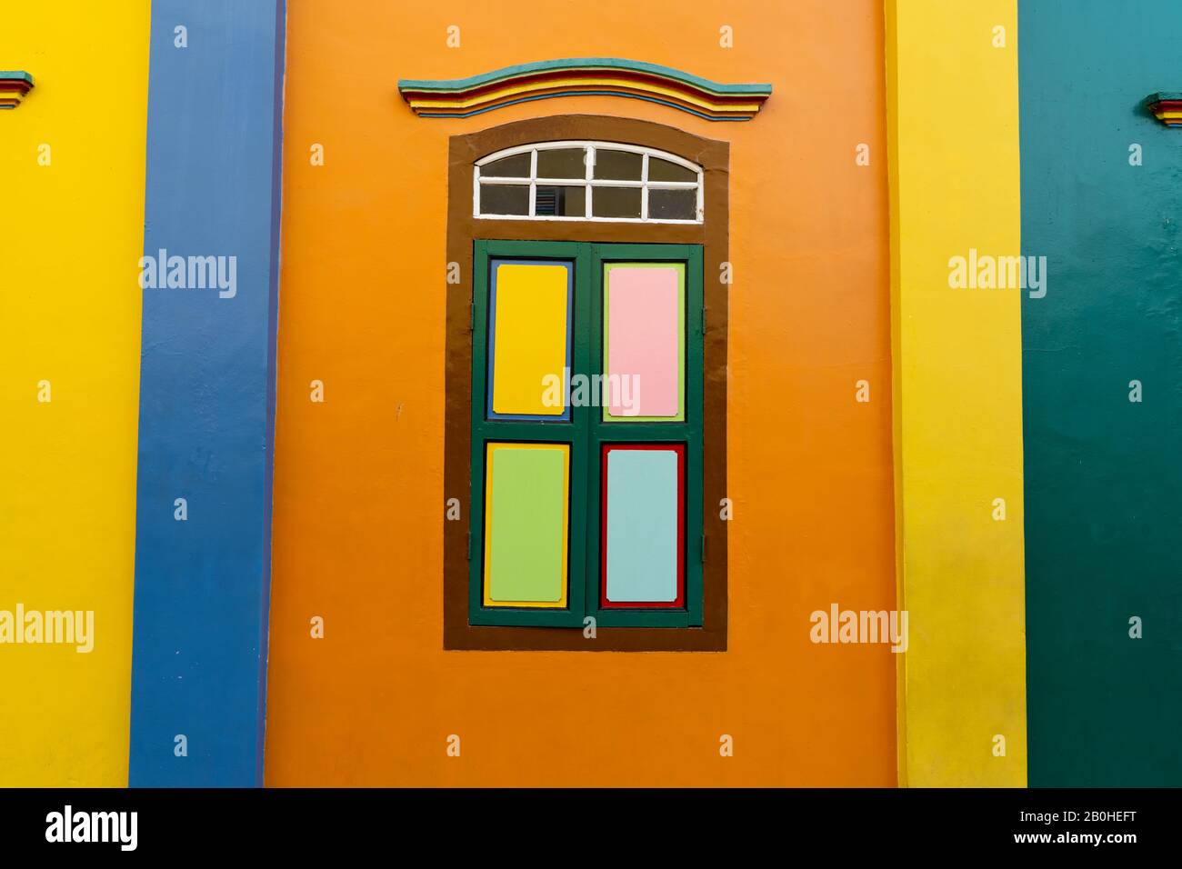 Window with coloured glass in an colored facade with a decorative arch ...