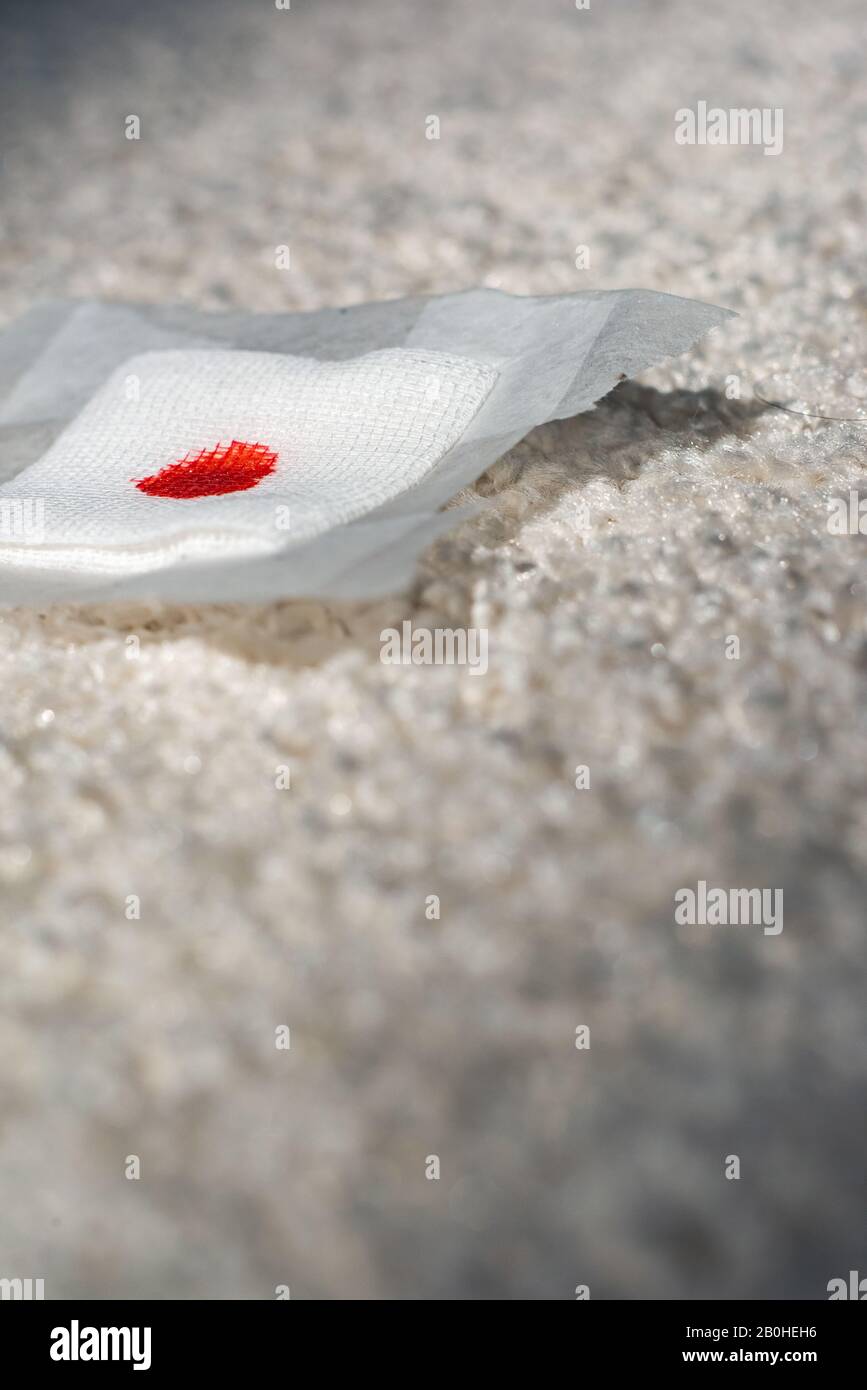 Fallen bandage with blood spot on white carpet Stock Photo - Alamy