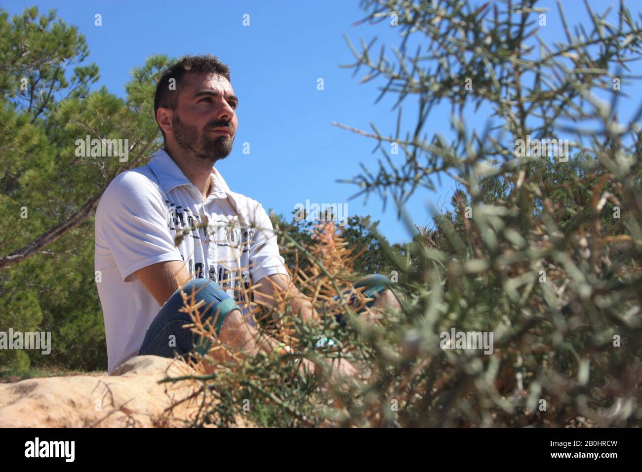 boy is resting on a summer day in the ibiza sun among the barren nature ...