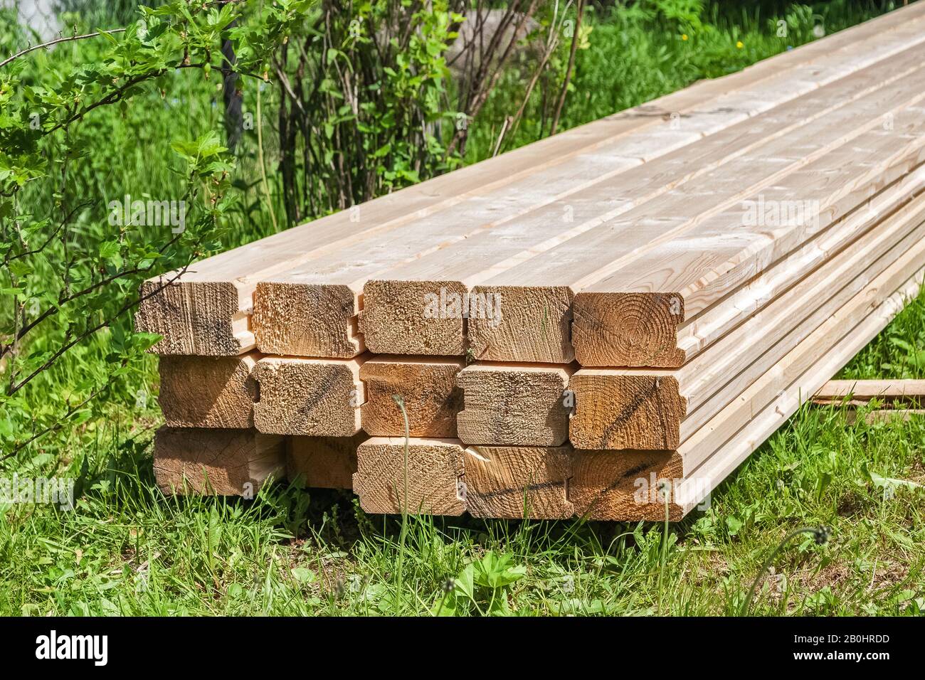Stacked in a pile shaped timber made of pine wood on the green grass ...