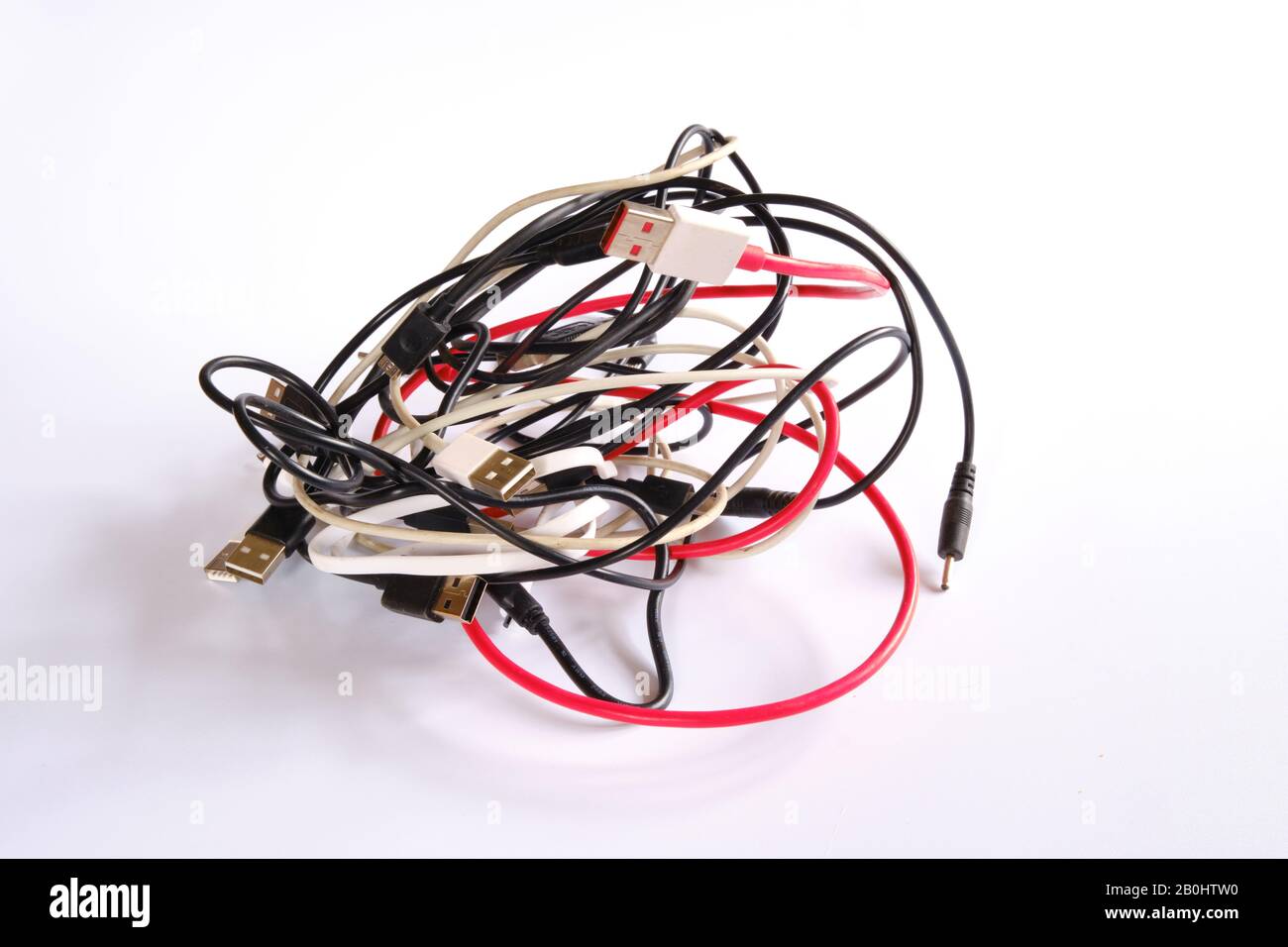 A mass bundle of assorted charging cables in a tangled ball mess ...