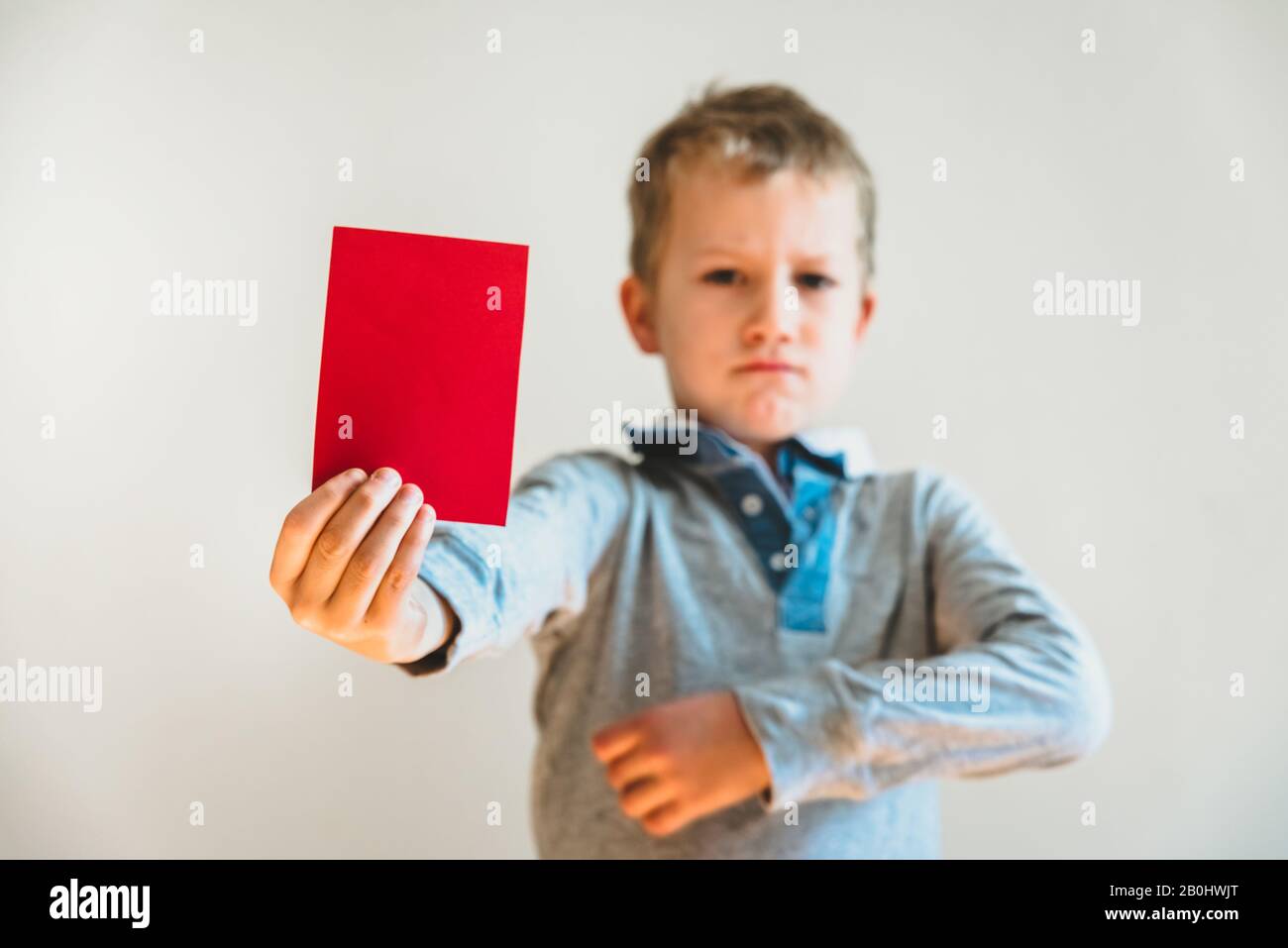Angry face child showing a red card as a warning, stop bullying concept ...