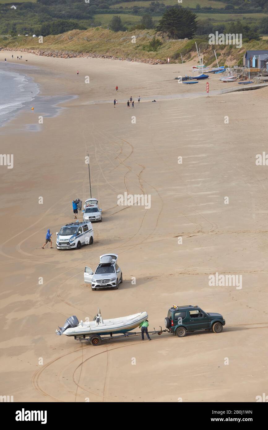 Car and boat on trailer, man securing trailer, and three other vehicles ...