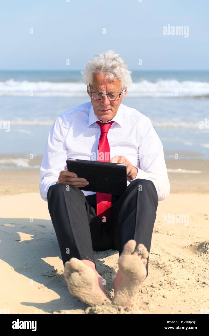 Business man in formal suit sitting and working with tablet at the ...