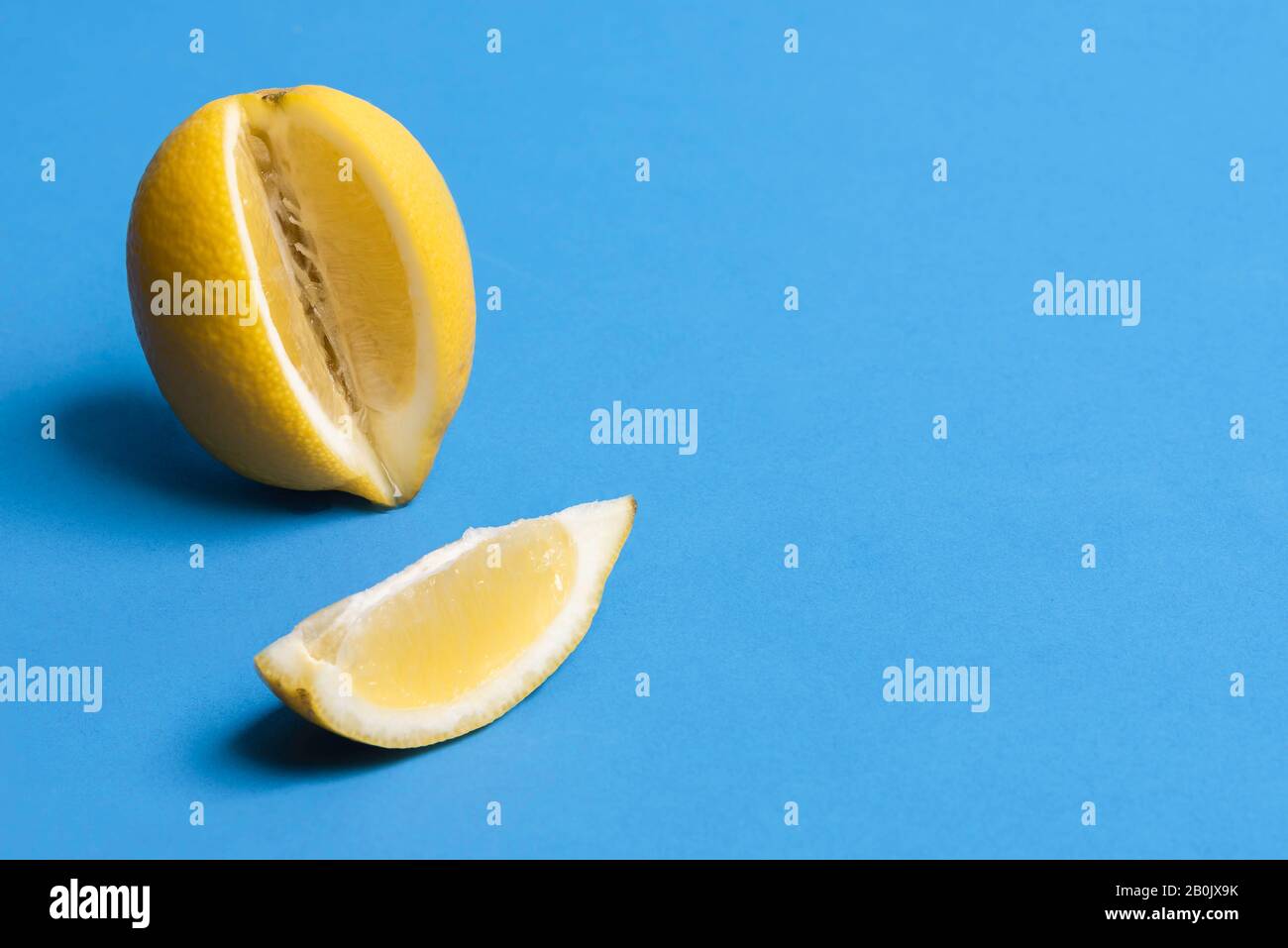 Single lemon fruit sliced and a slice of lemon isolated on blue ...