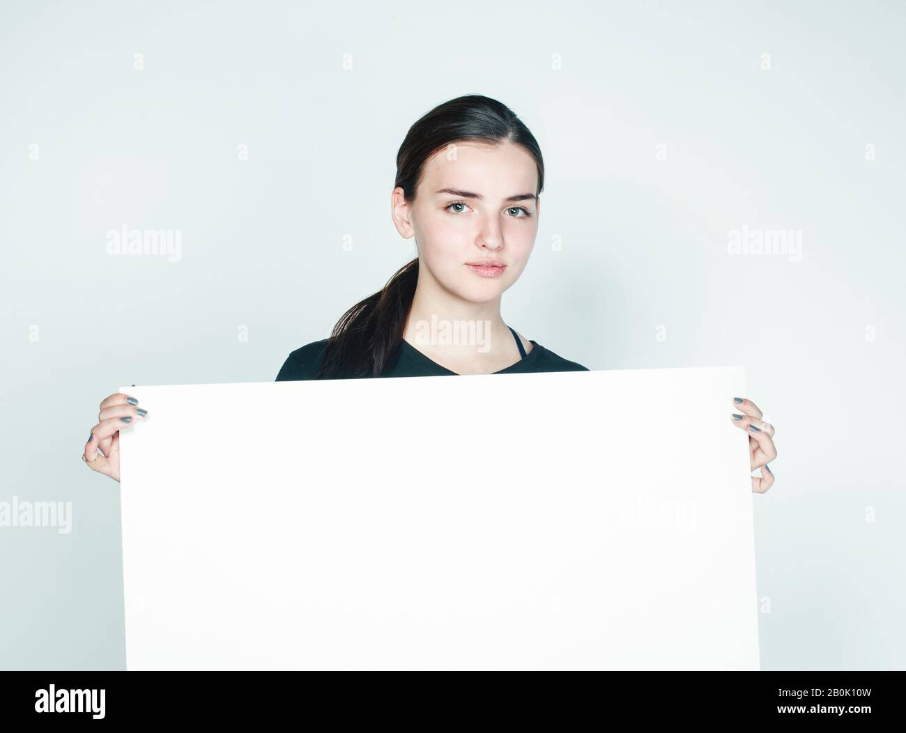 young pretty brunette girl with placard on white background wearing ...
