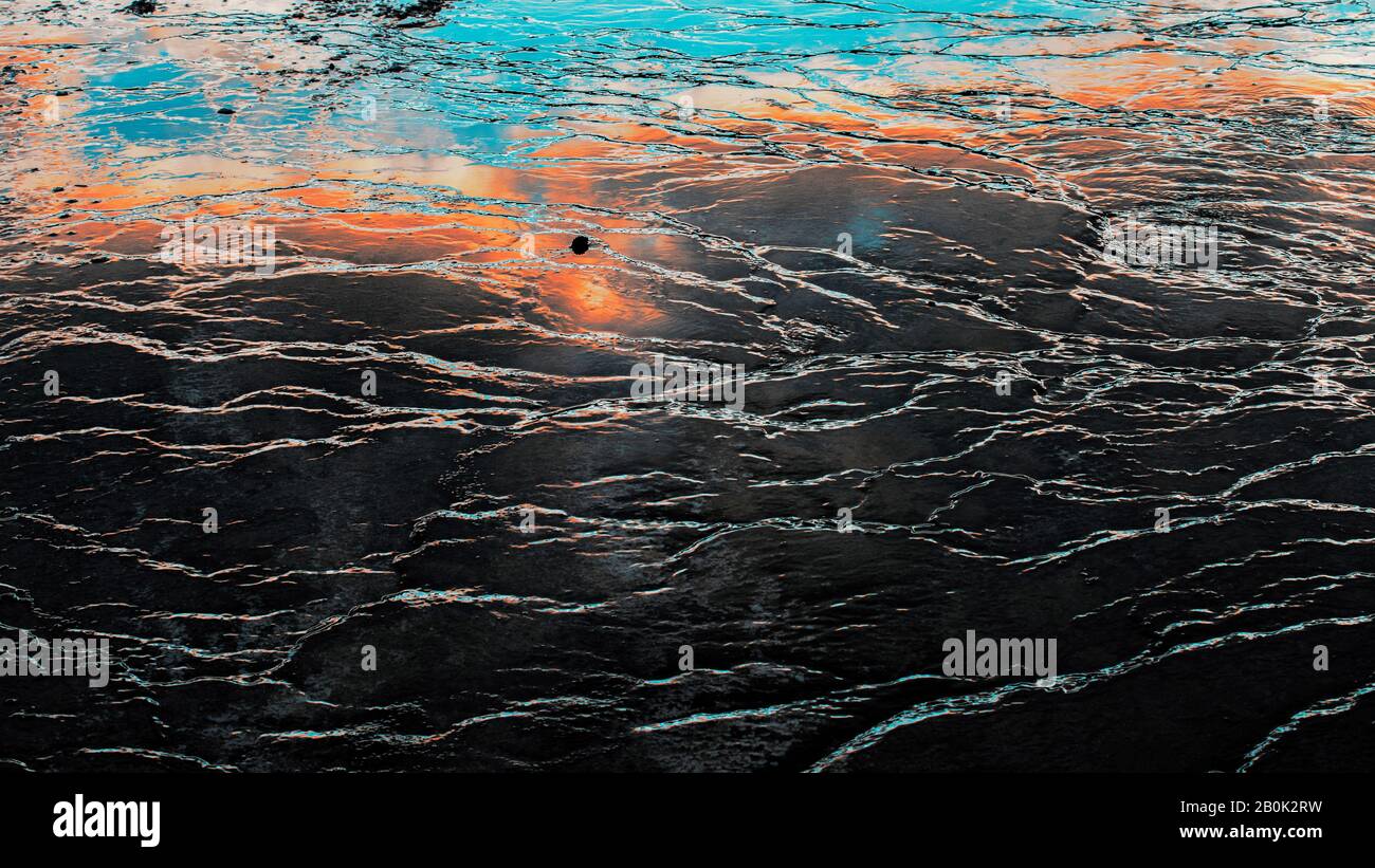 Black rock surface with bright orange and blue light reflecting off the ...