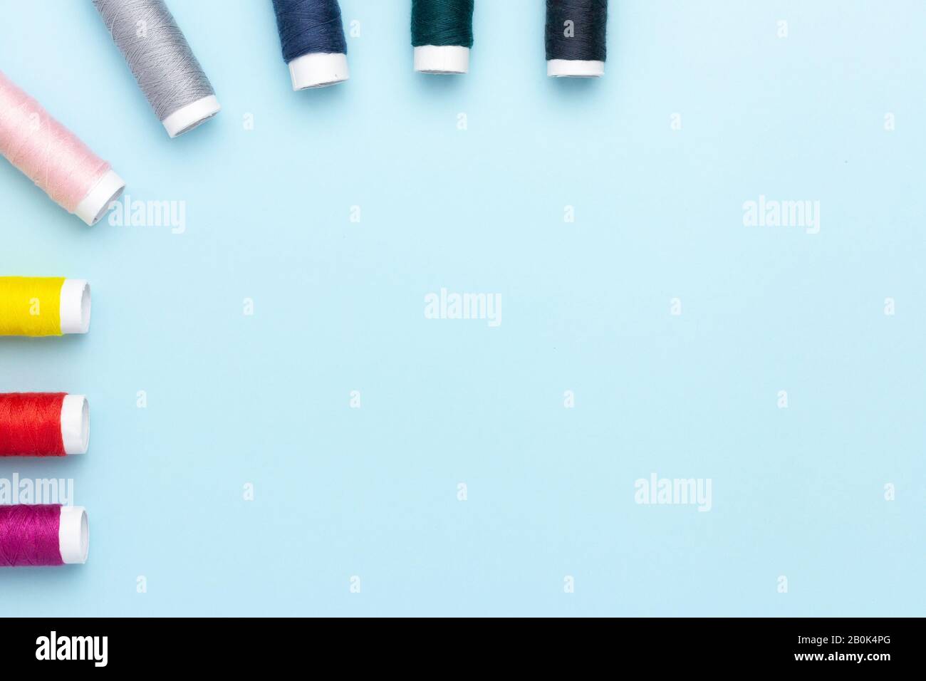 Colorful sewing threads on a blue background Stock Photo - Alamy