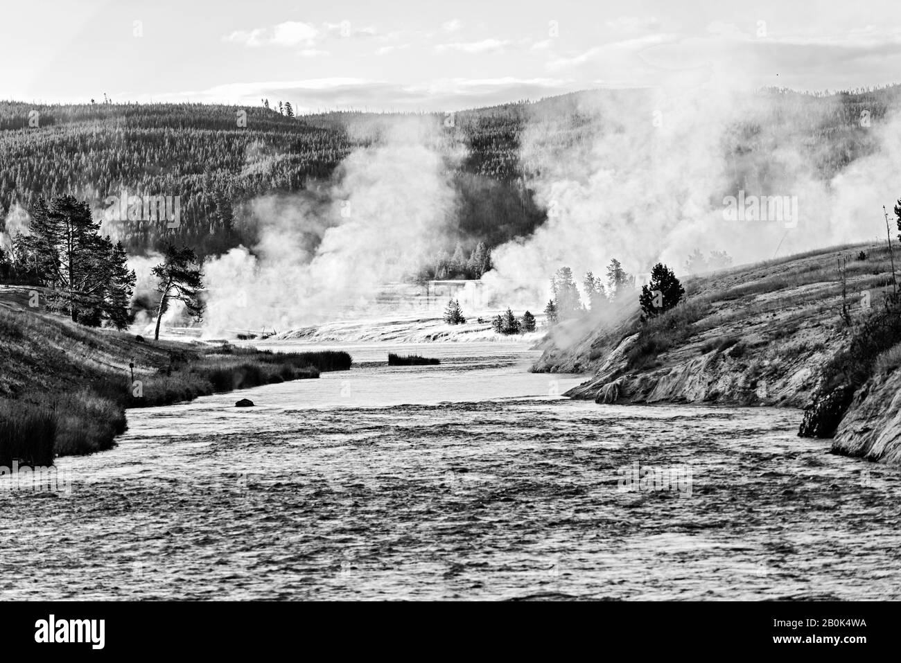 Mountains and geysers venting steam as river flows through landscape ...