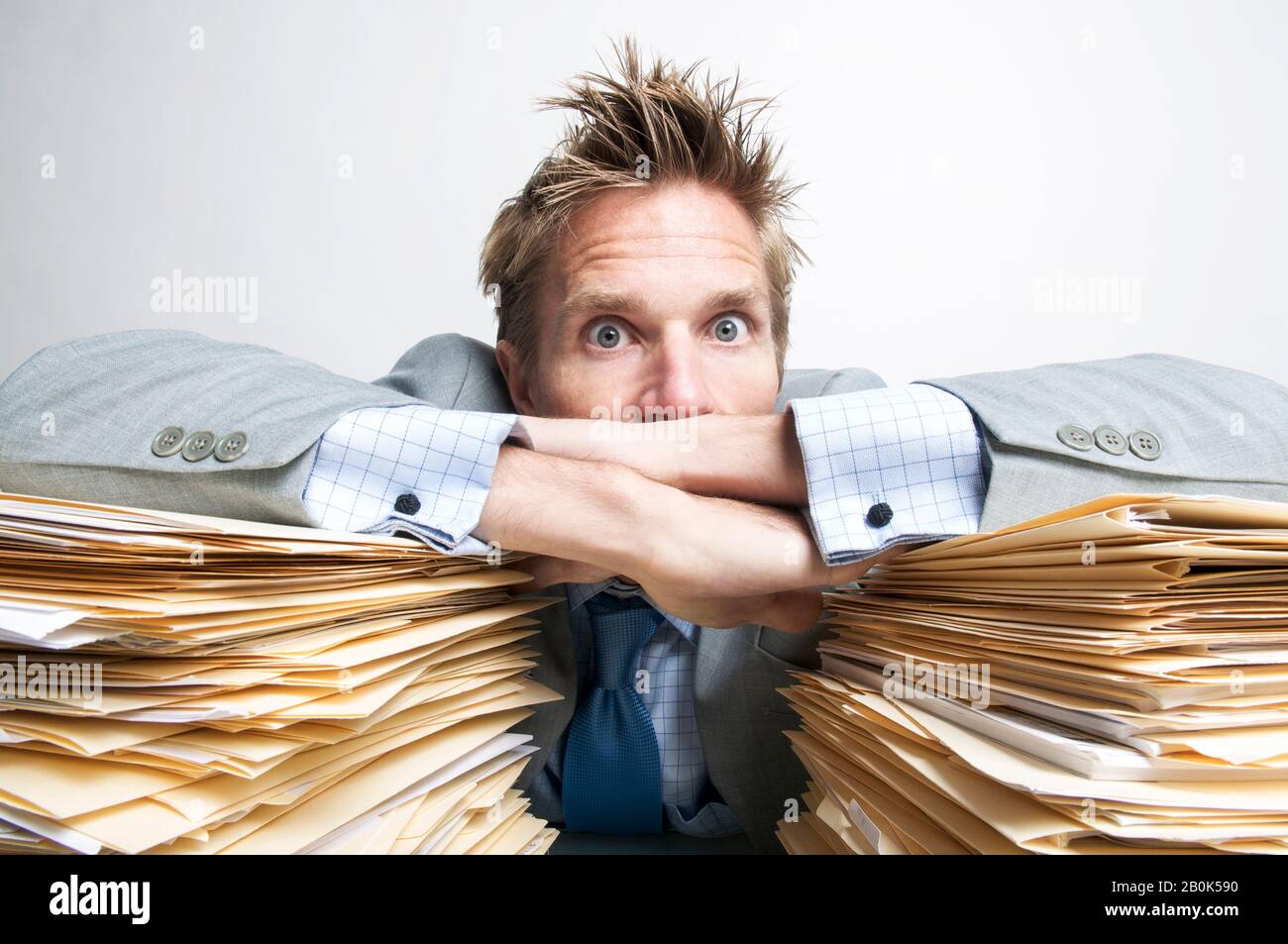 Overwhelmed office worker resting on the huge pile of paperwork on his ...
